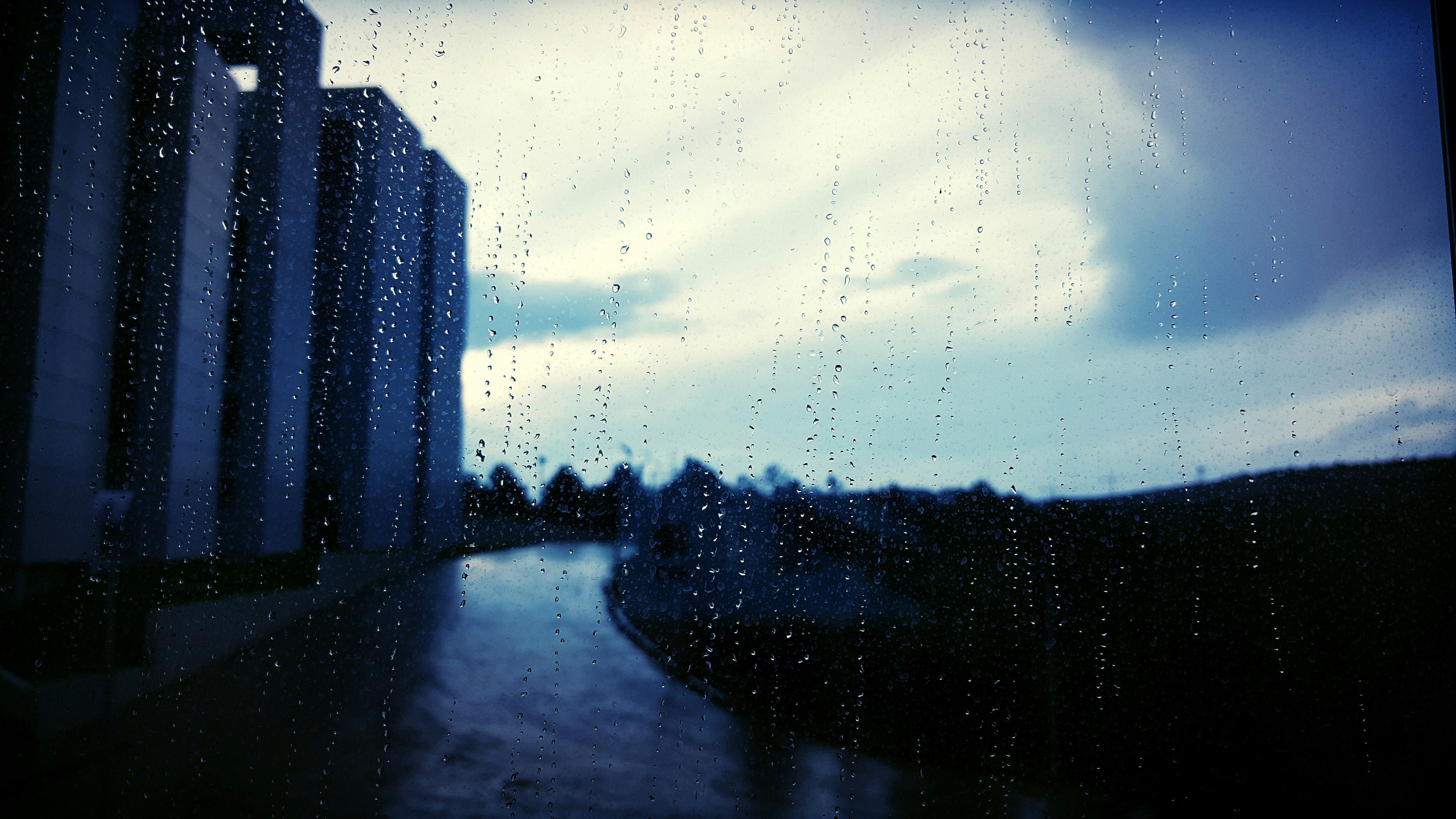 A view of a building through a rain covered window photo – Free Blue ...