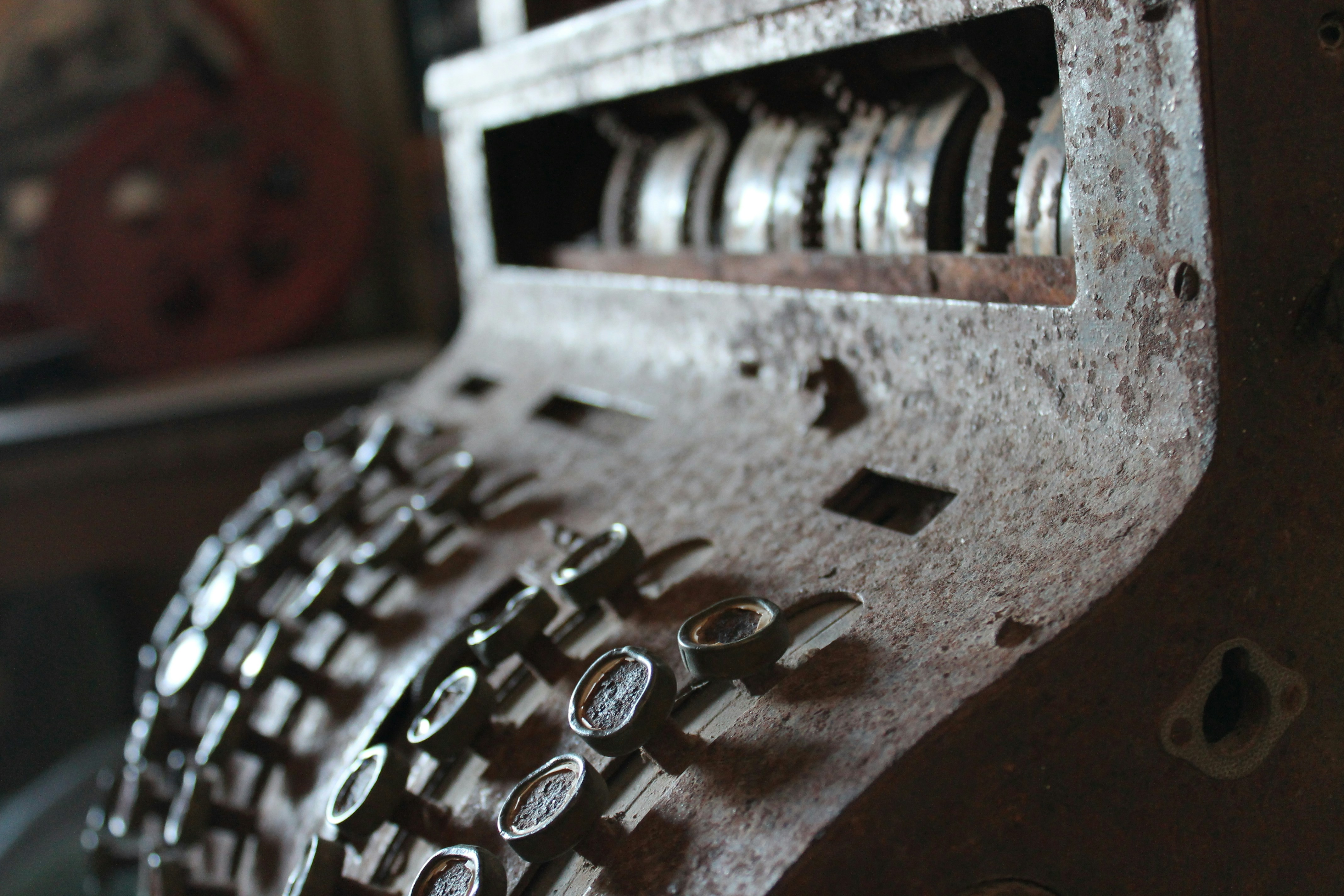 Close-up of an antique cash register showcasing its weathered keys and intricate mechanisms. The rust speaks to its long history and the stories it holds.