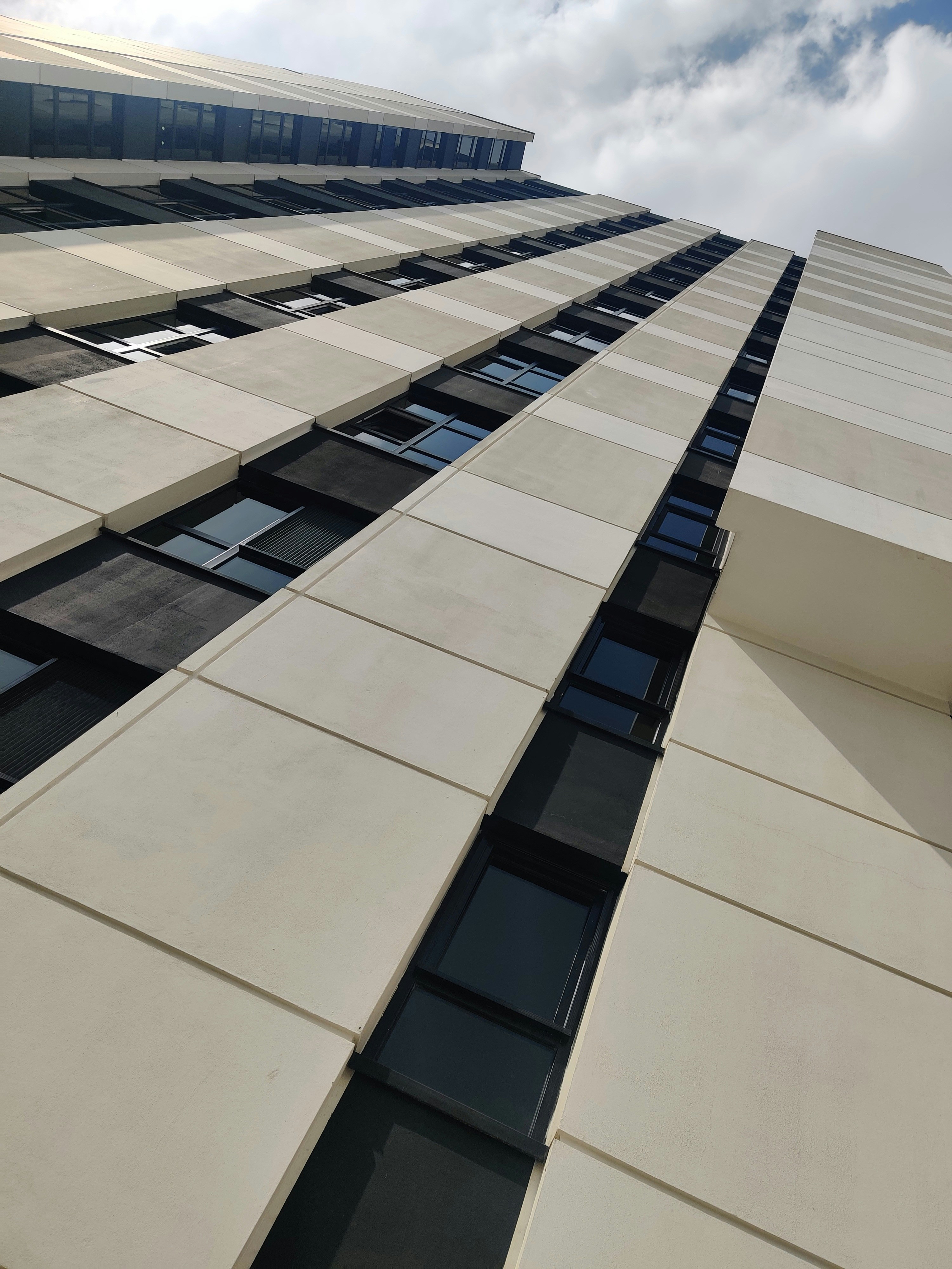 Angular view of a modern building showcasing its geometric lines and contrasting colors of white and black. The image emphasizes the architectural design and structural elements.