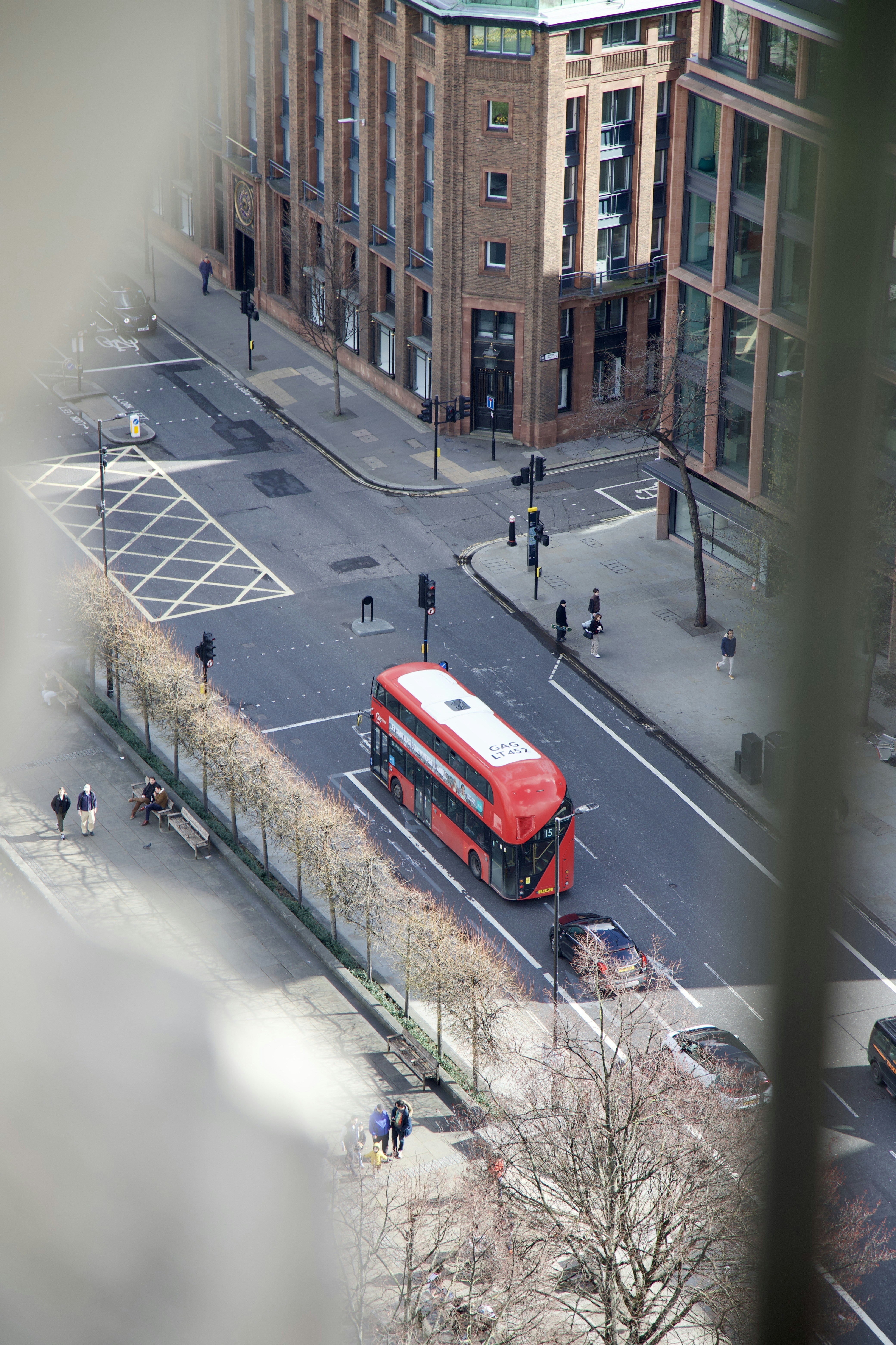 A red bus driving down a street next to tall buildings photo – Free ...