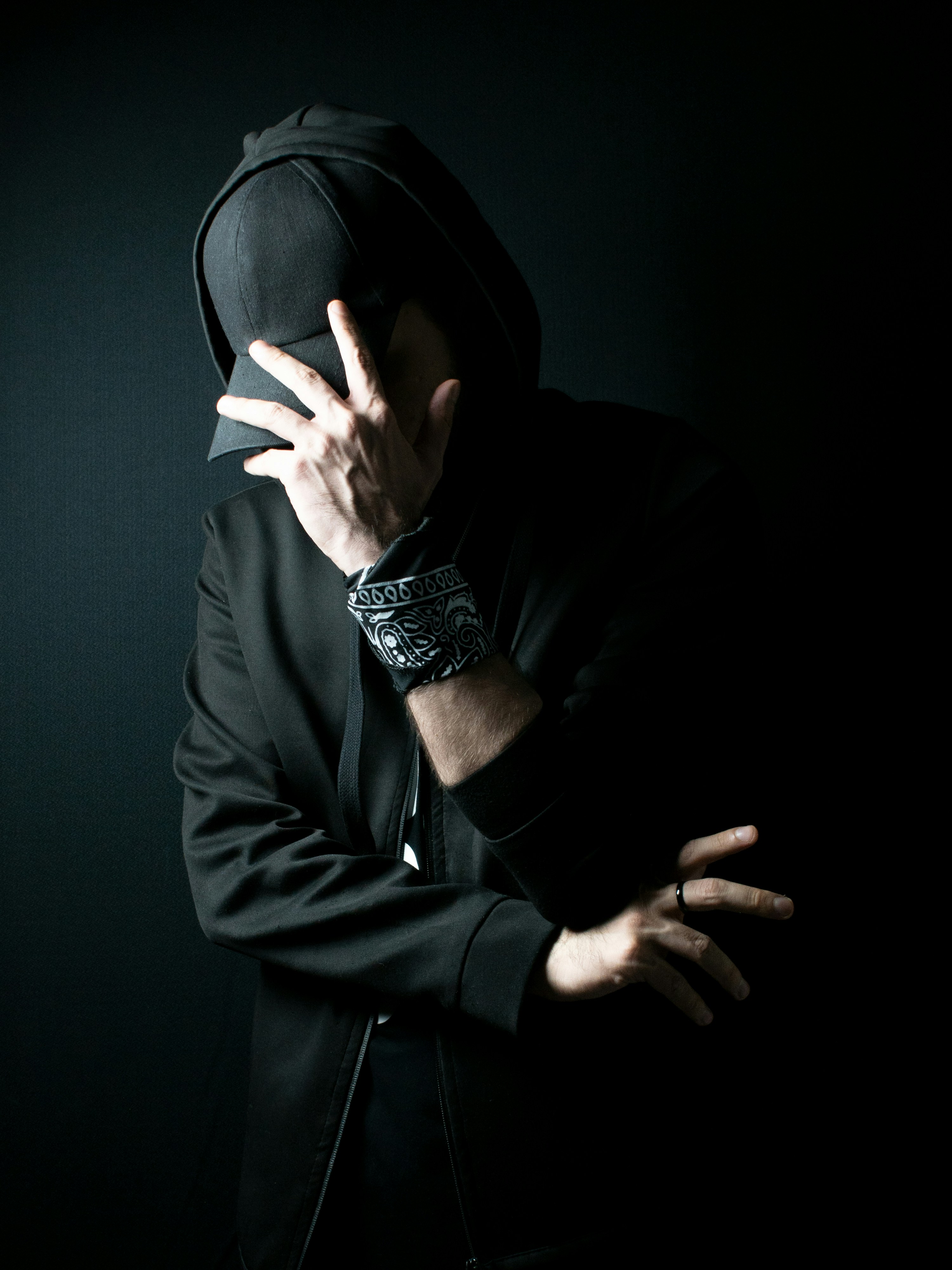 A man in a black hoodie covering his face with his hands photo – Free ...