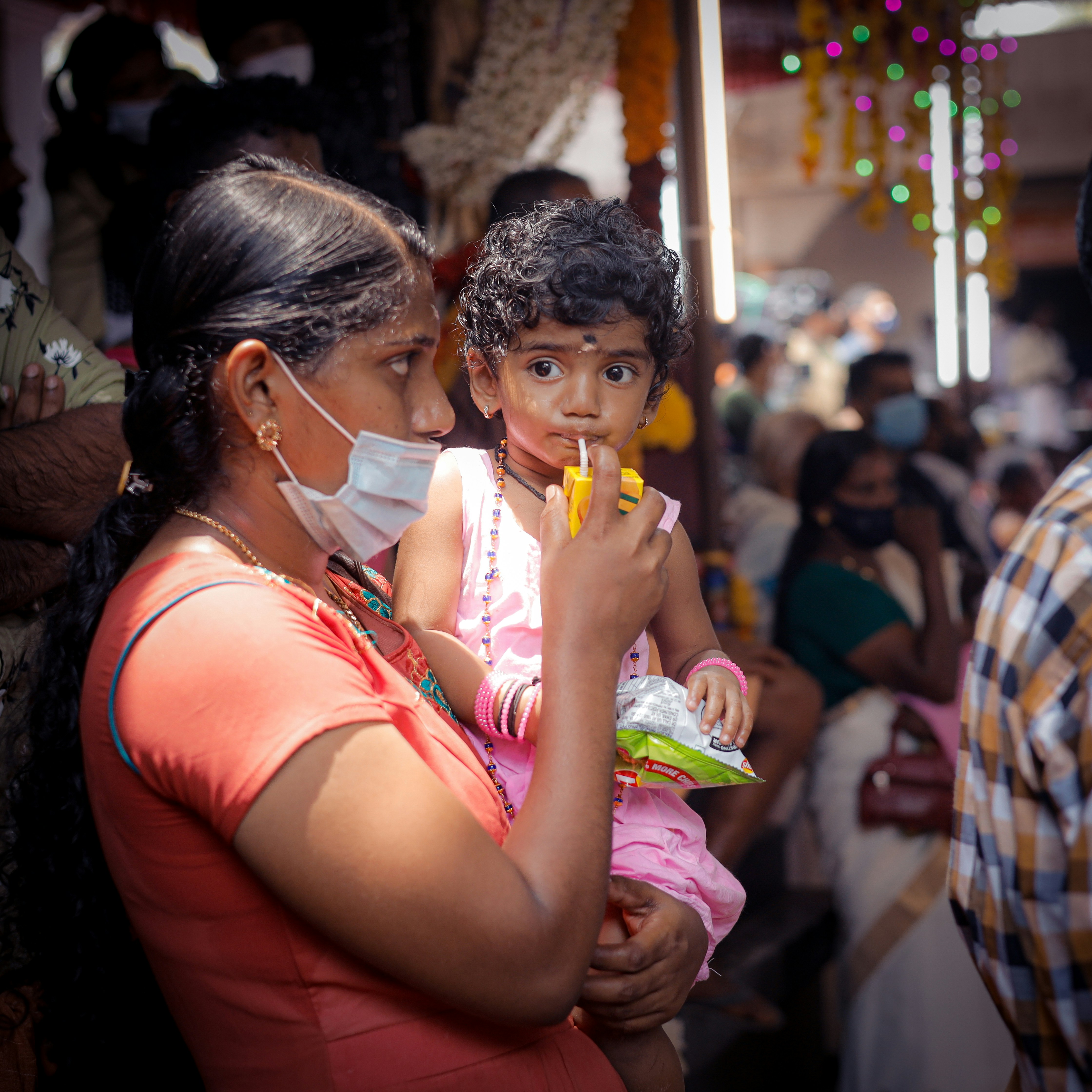 a woman holding a child wearing a face mask
