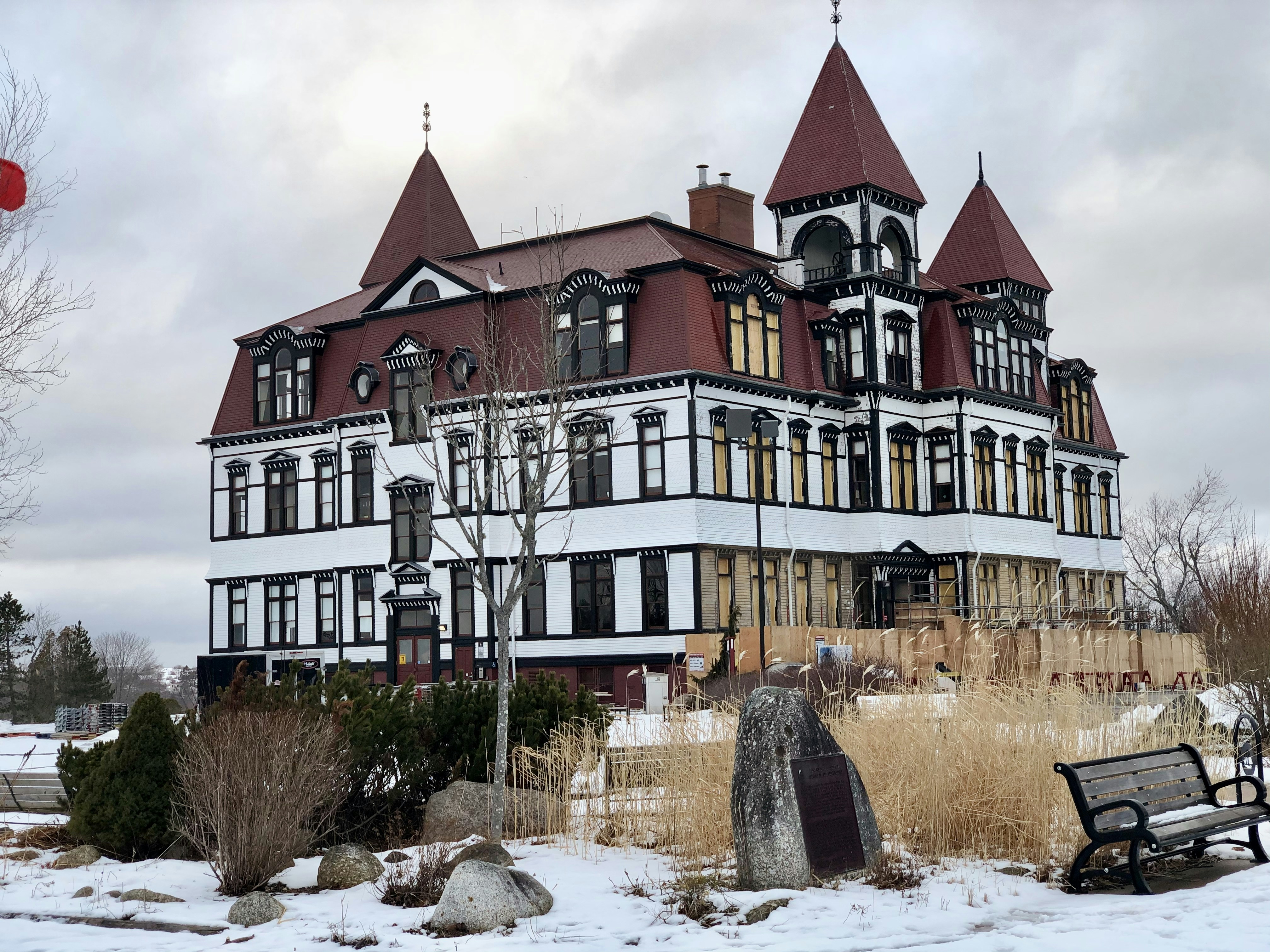 Historic building with ornate architecture and a striking red roof, surrounded by winter landscape and snow-covered ground.