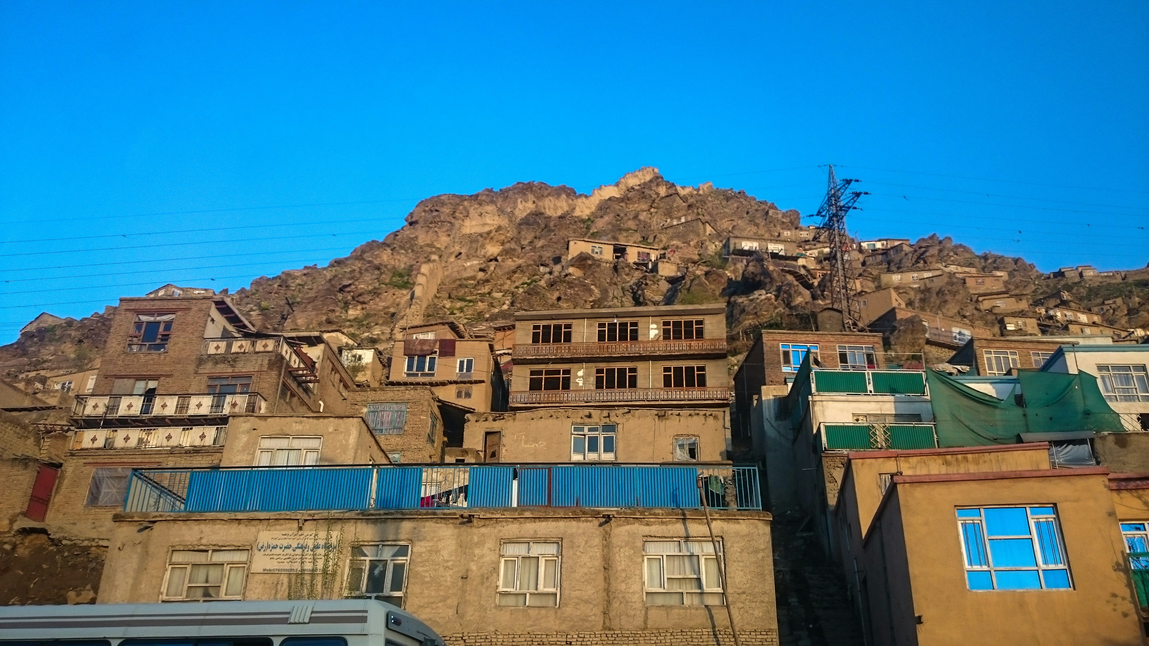 Cluster of hillside homes basking in warm sunlight, set against a vibrant blue sky.