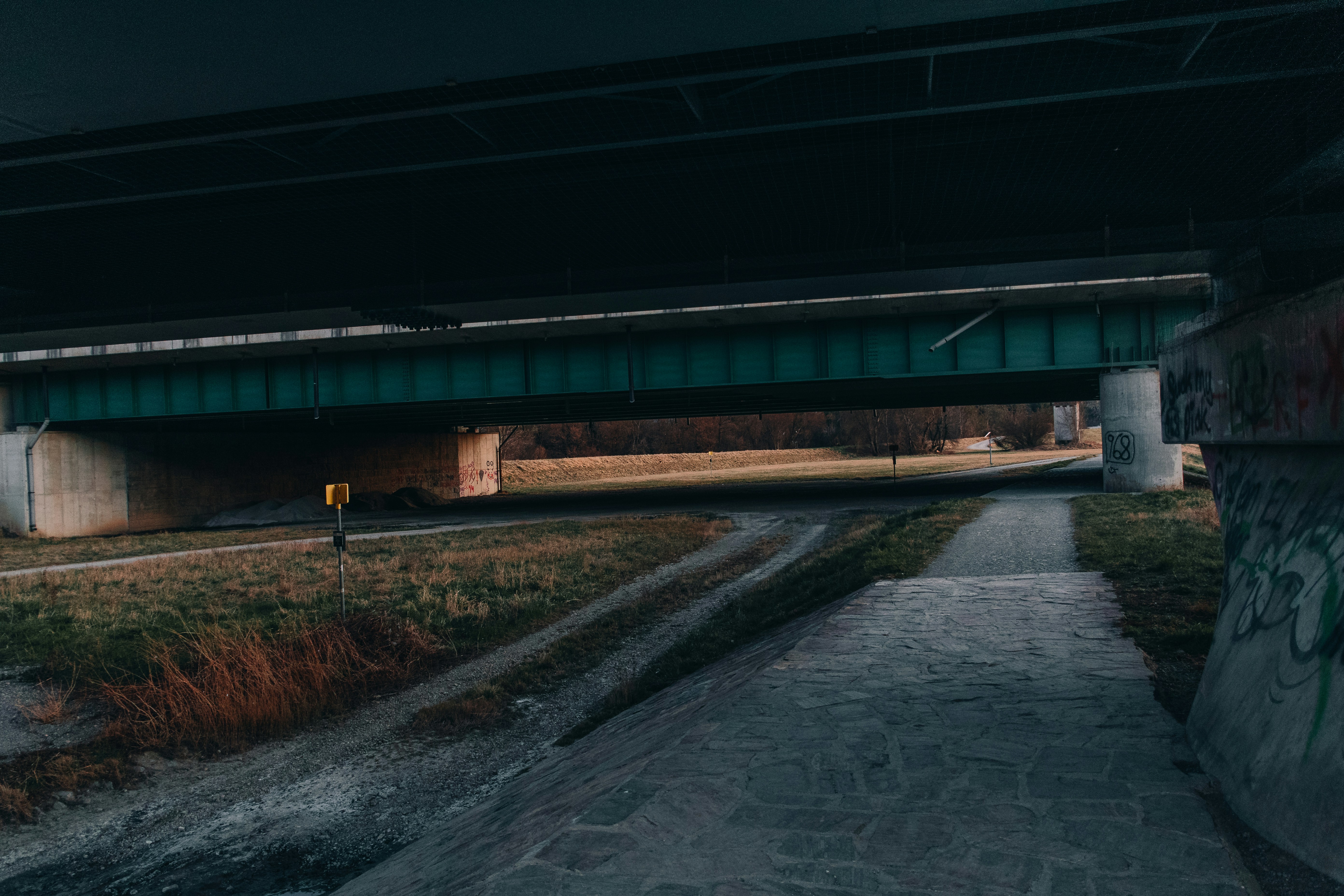 A walkway under a bridge with graffiti on it photo – Free Bridge Image ...