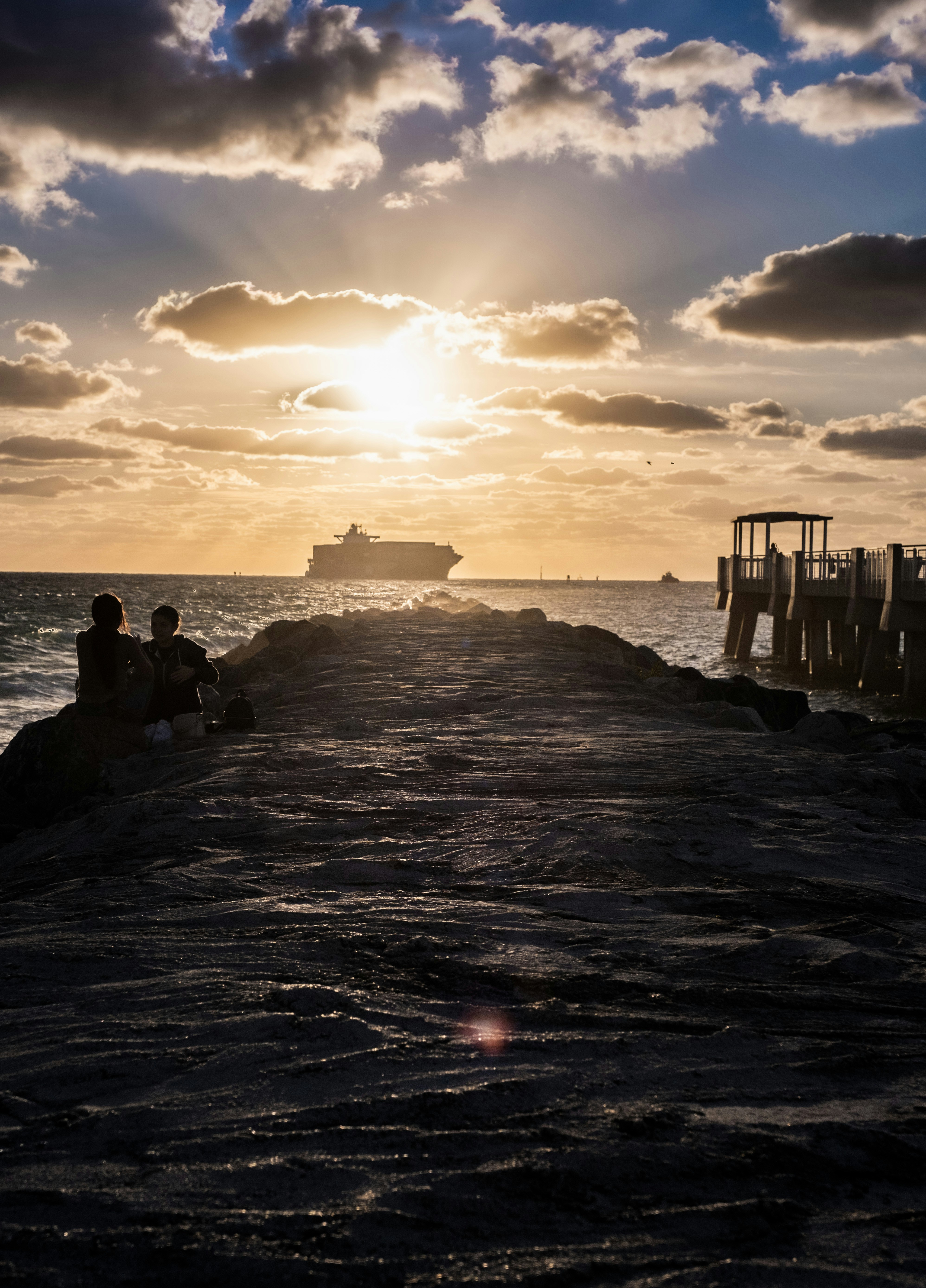 Un couple de personnes assises au sommet d’une jetée photo – Photo ...
