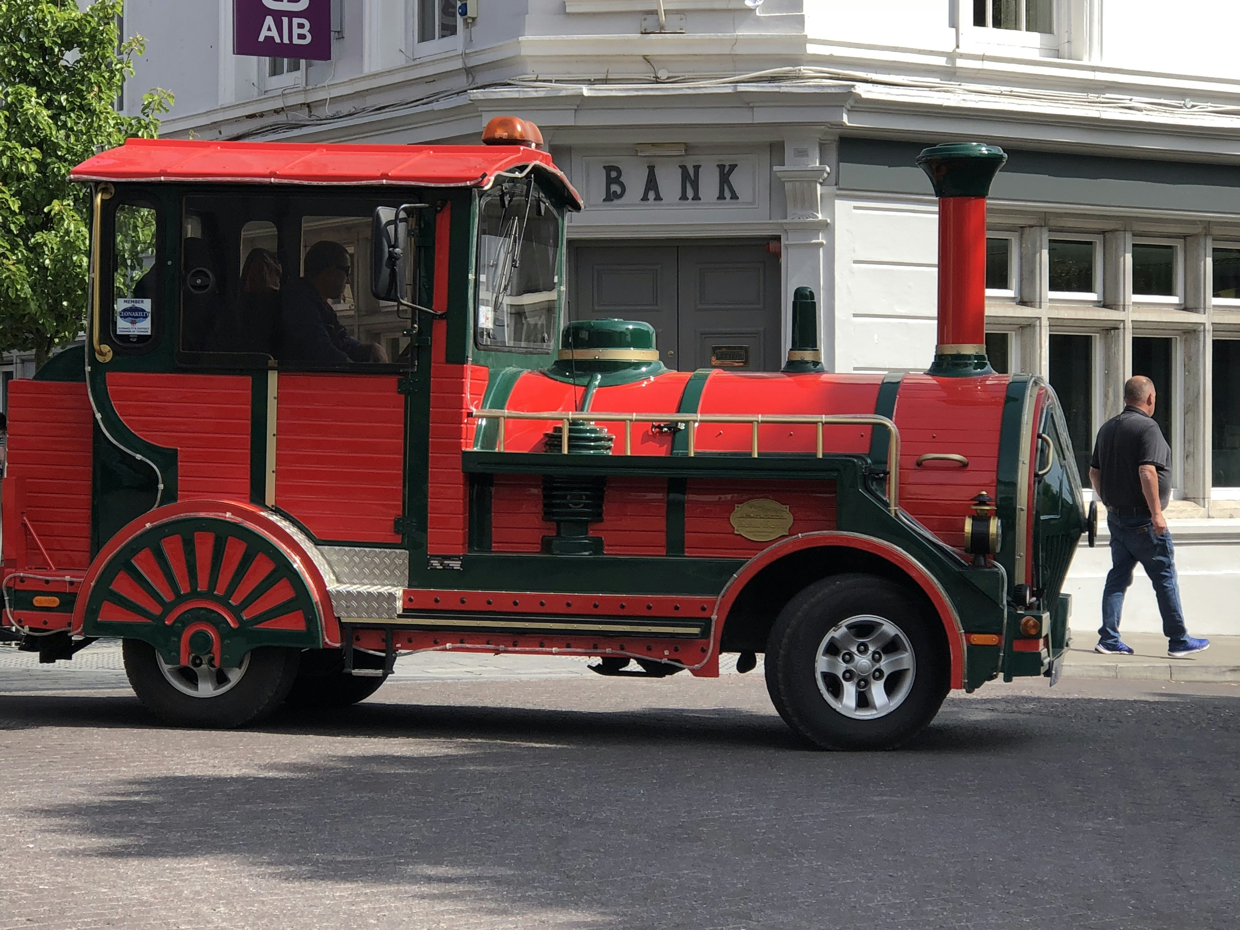 a red and green train is driving down the street