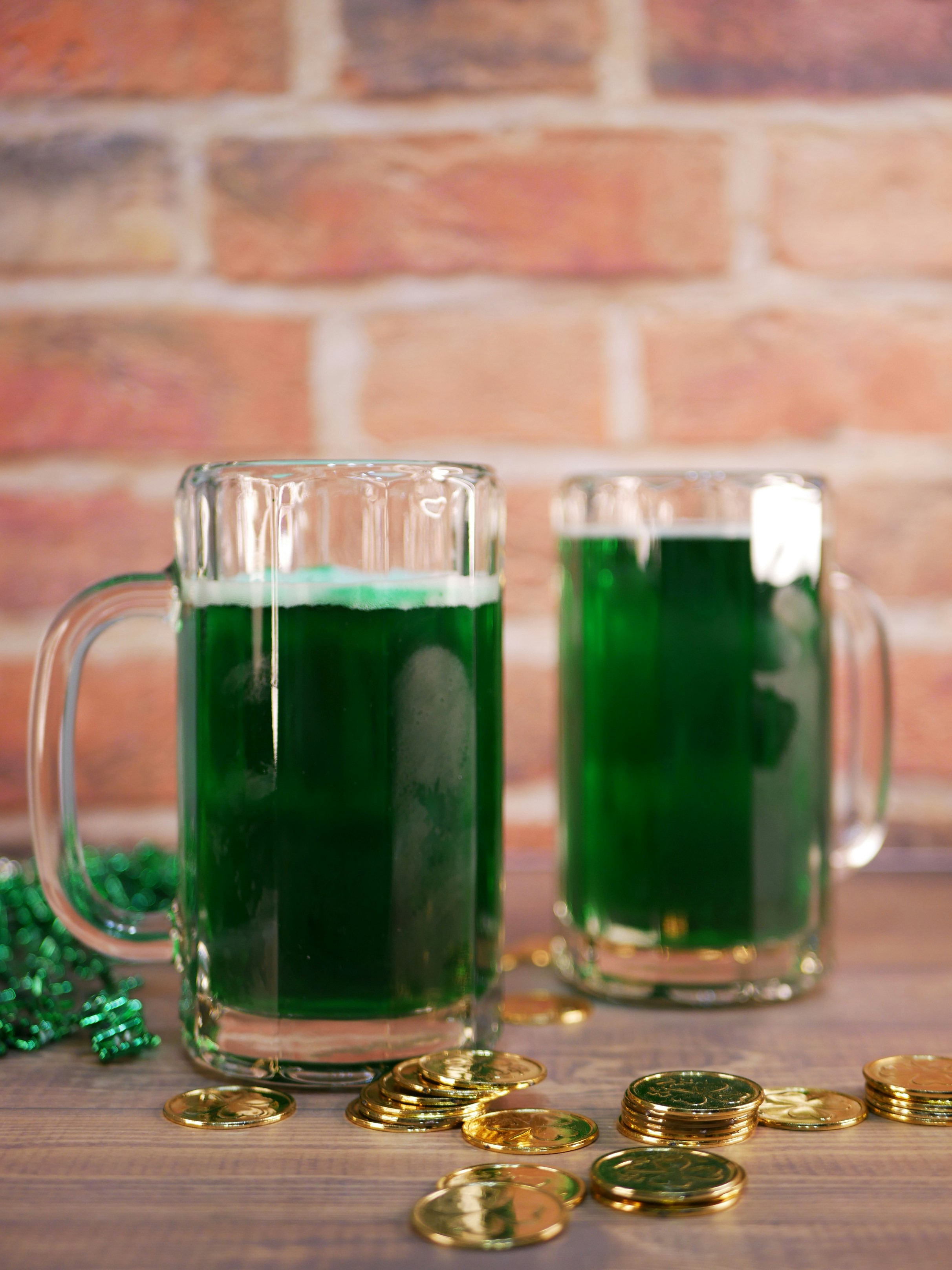 Emerald Drafts by the Brick Wall: Glass Mugs, Gold Coins, and Green Glow