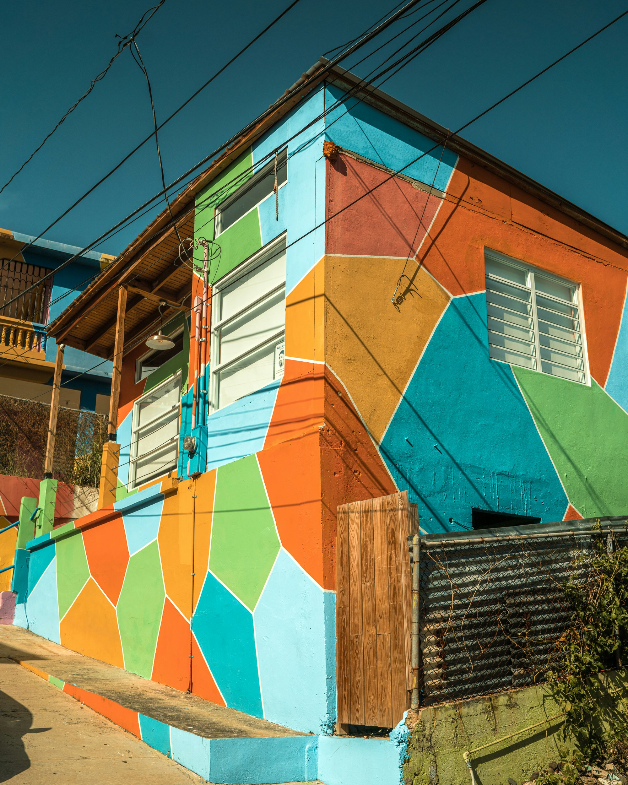 Colorful geometric mural adorning a building in a lively neighborhood, showcasing artistic flair and urban culture.