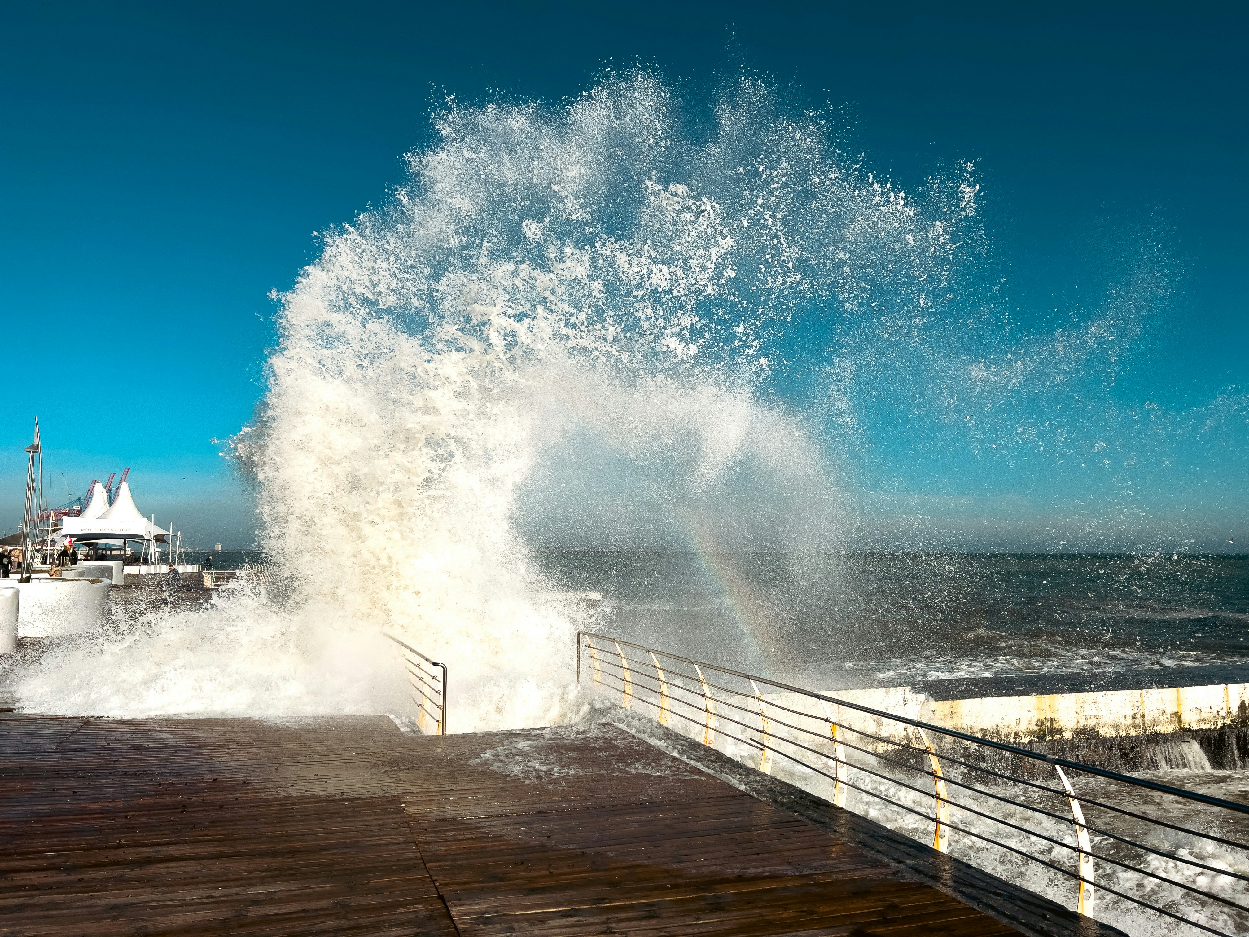 A large wave crashing over a wooden pier photo – Free Wave Image on ...