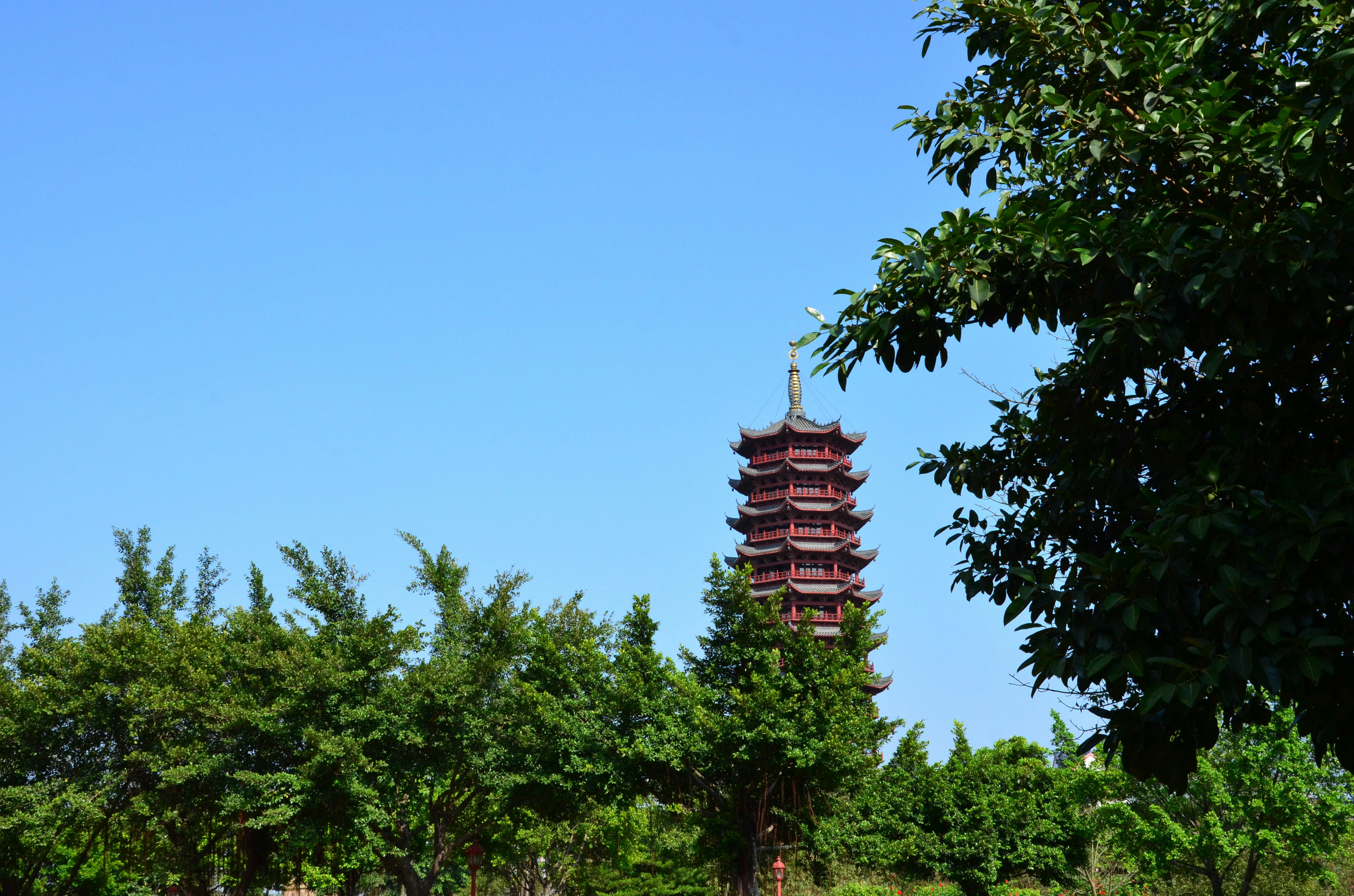 Crimson Pagoda Rising Through the Park Canopy under a Clear Blue Sky
