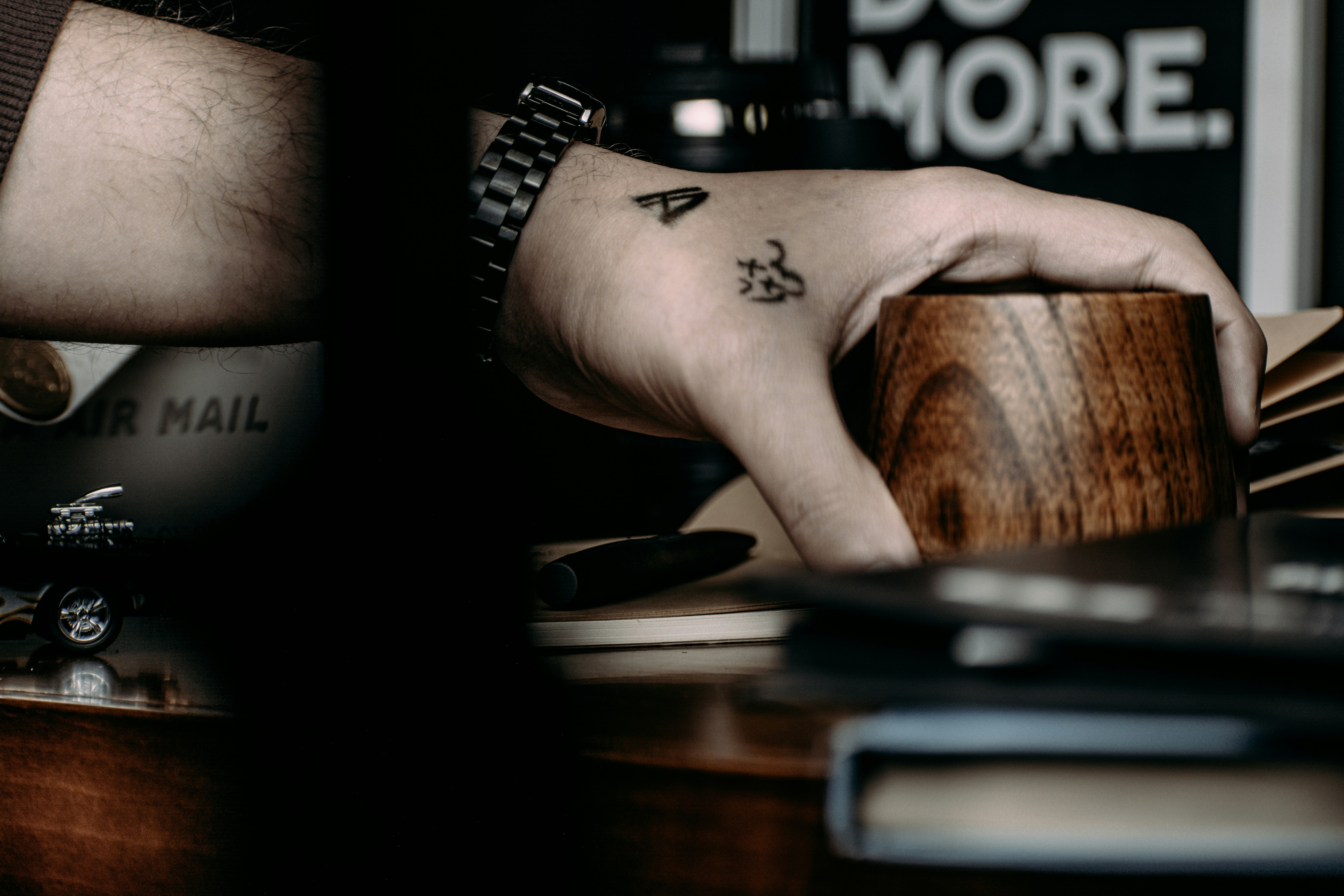 Grip and Grain: A Tattooed Hand Anchored to Walnut in Low Light