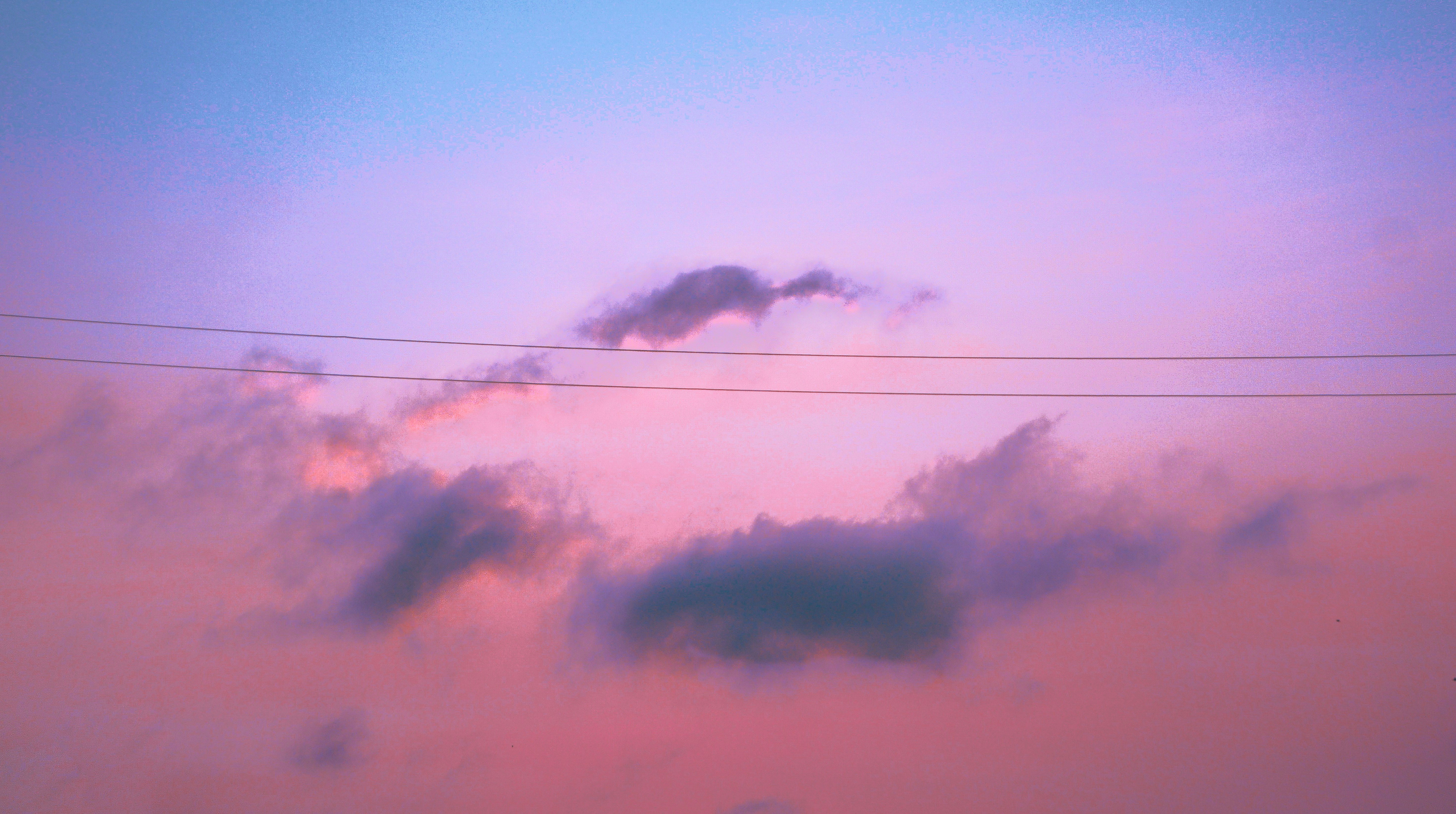 Soft pastel clouds drifting in a gradient sky at dusk, with power lines subtly intersecting the scene.