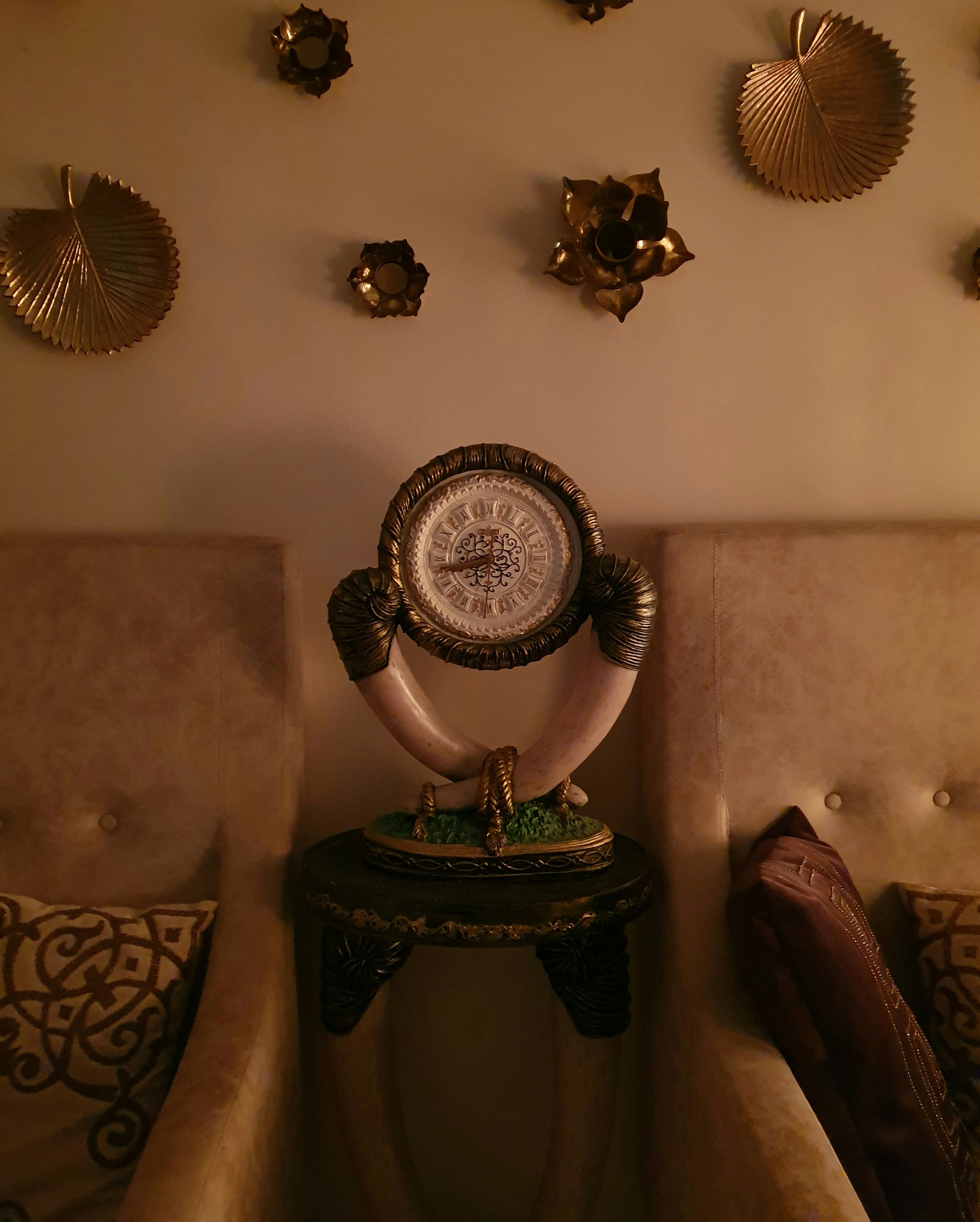 a clock sitting on top of a table next to two chairs