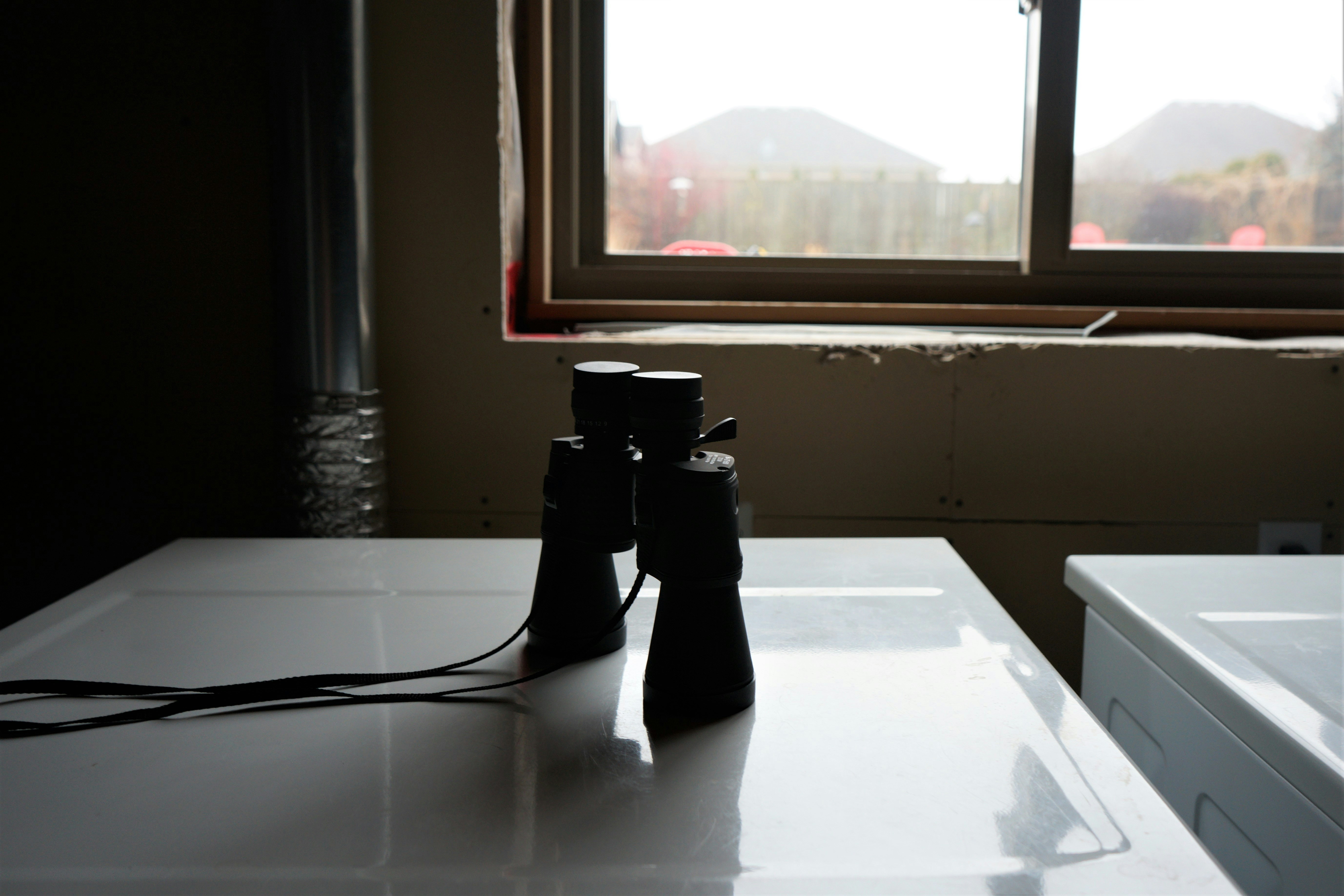 Silent Observation: A Row of Binoculars on a Windowed Worktable