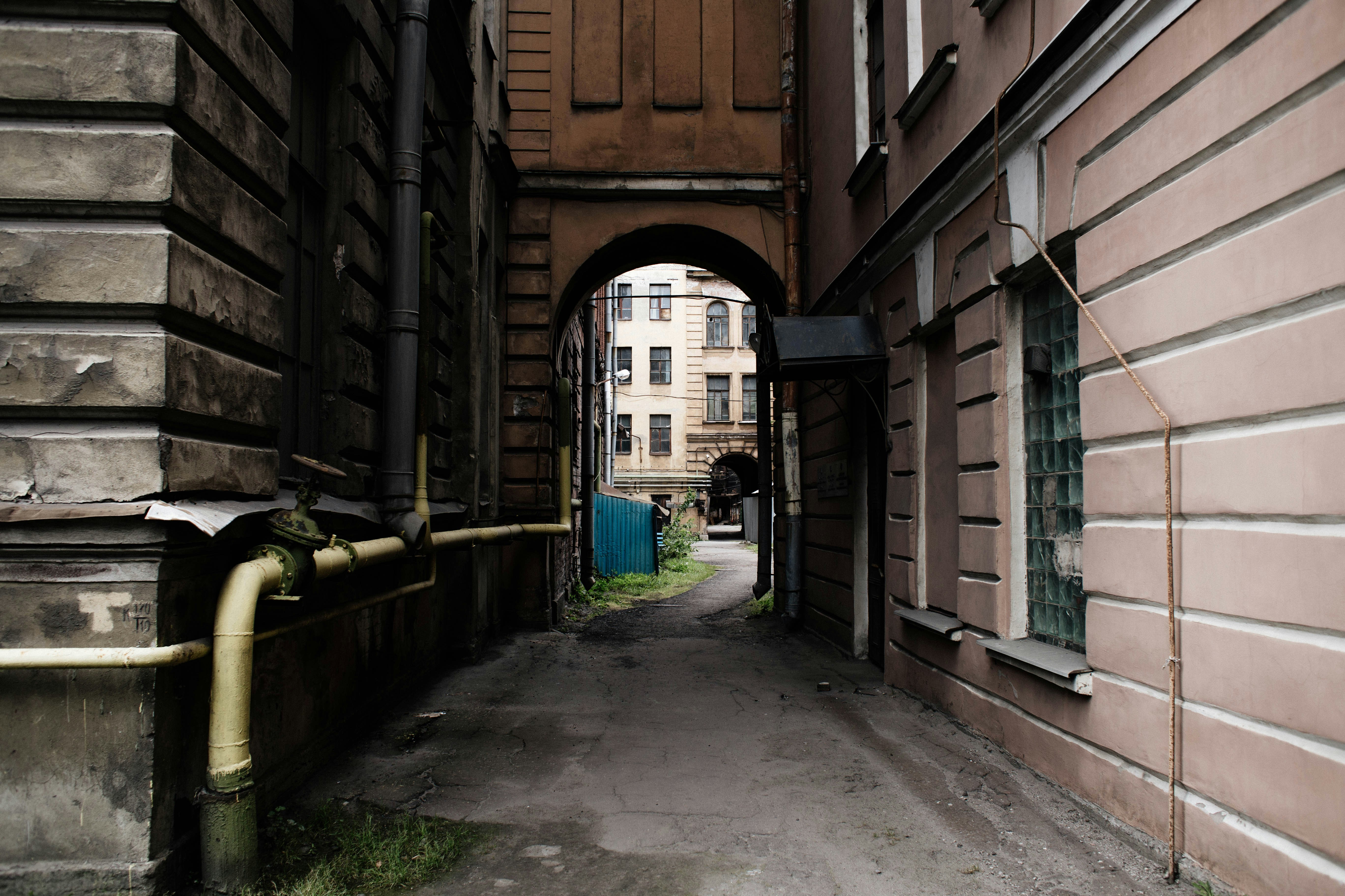 a narrow alley with a yellow pipe going through it