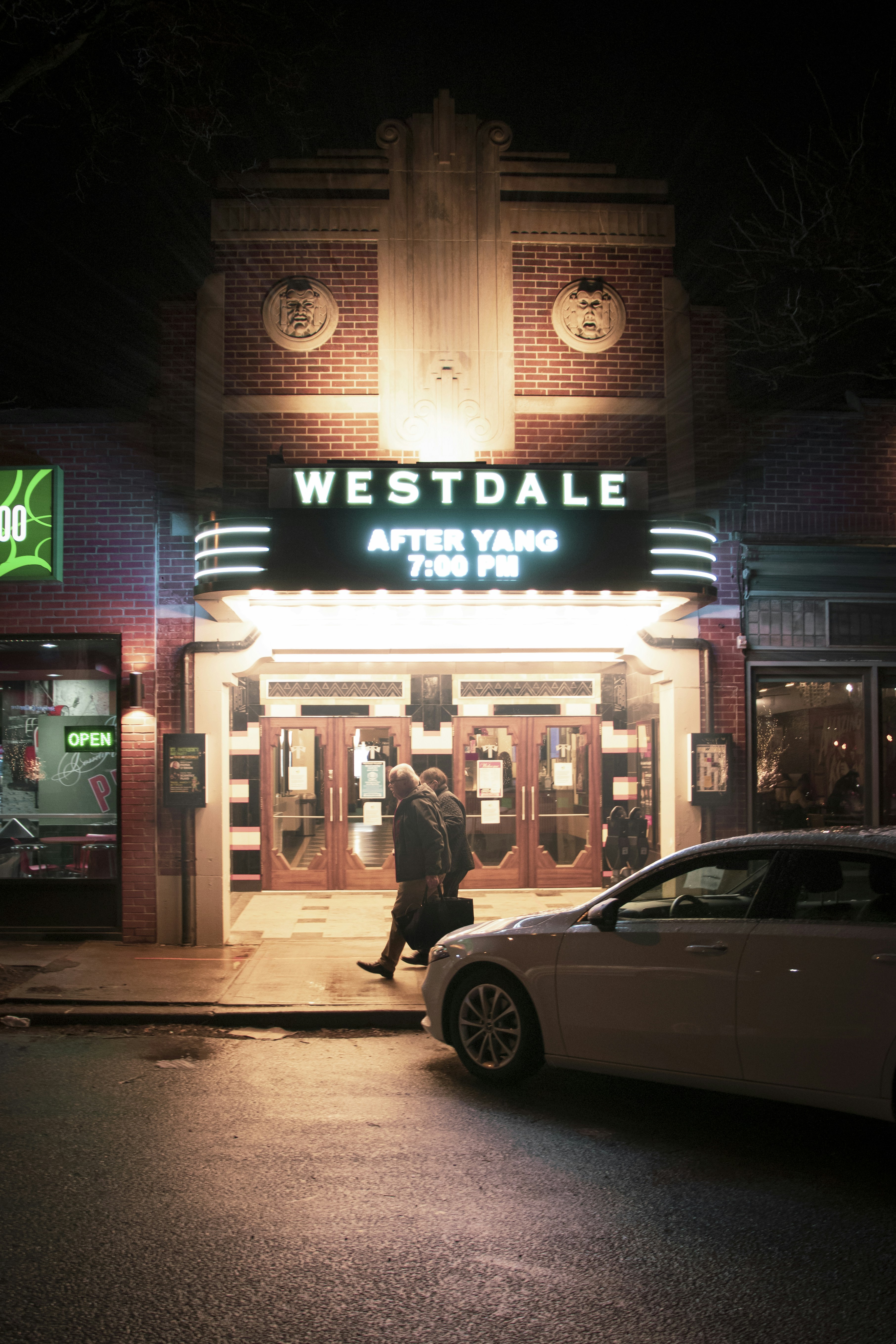 Historic Westdale Theatre illuminated at night with patrons approaching the entrance. Neon lights highlight the marquee's details.