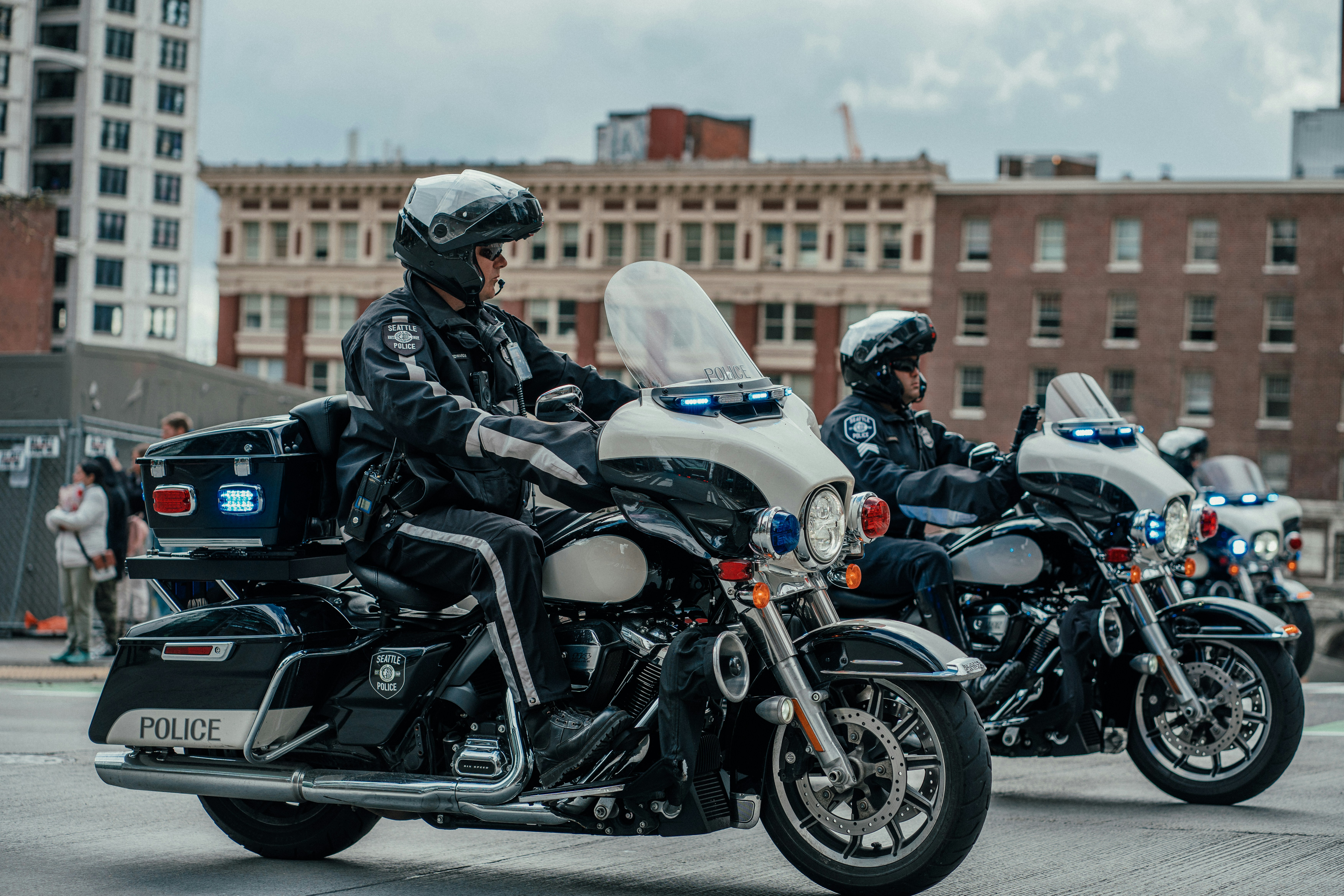 Two police officers on motorcycles navigate the city streets, showcasing law enforcement's presence and readiness. The scene captures the essence of urban policing.