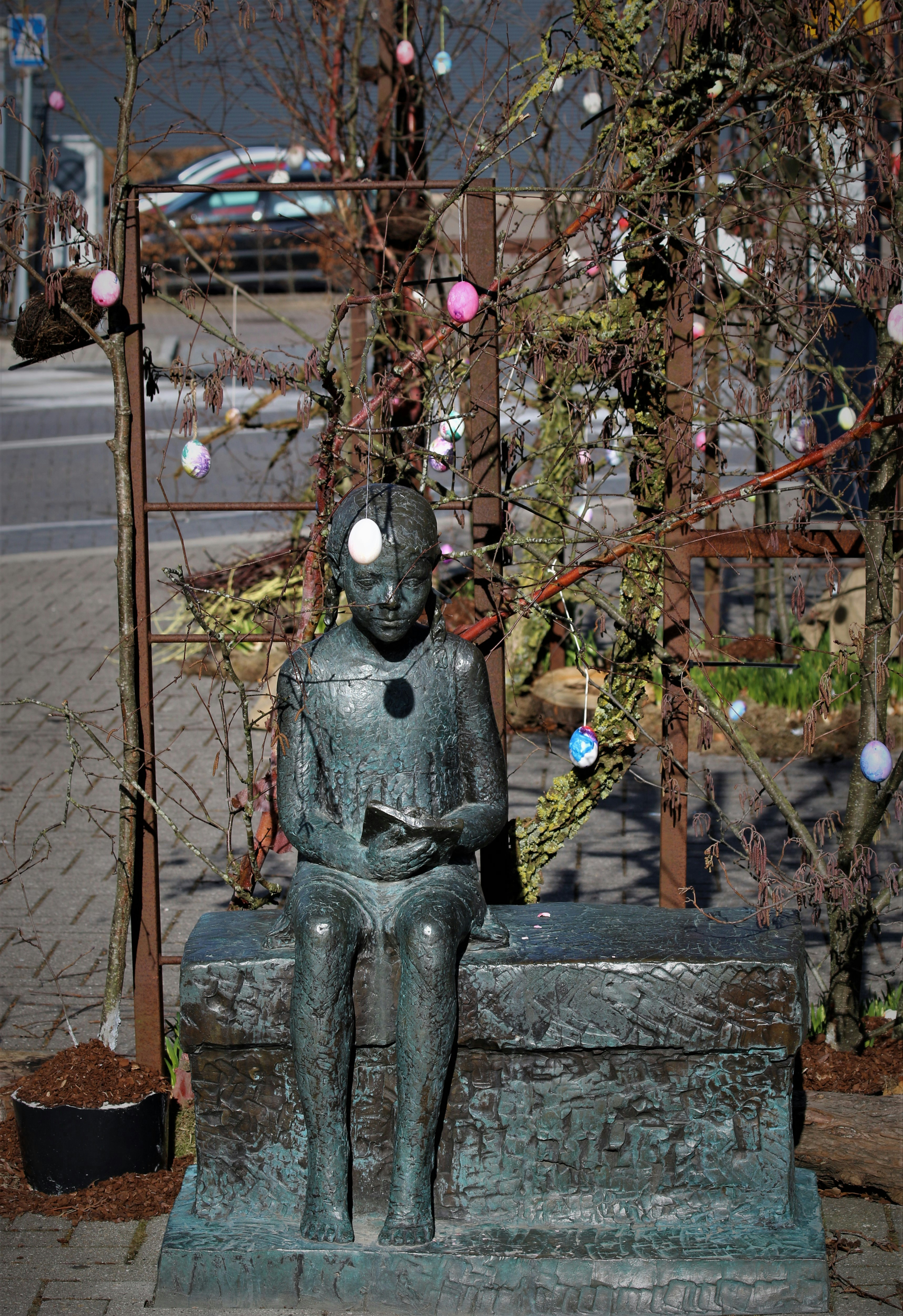 Quiet Bronze Figure Seated Amid Colored Orbs in an Urban Plaza
