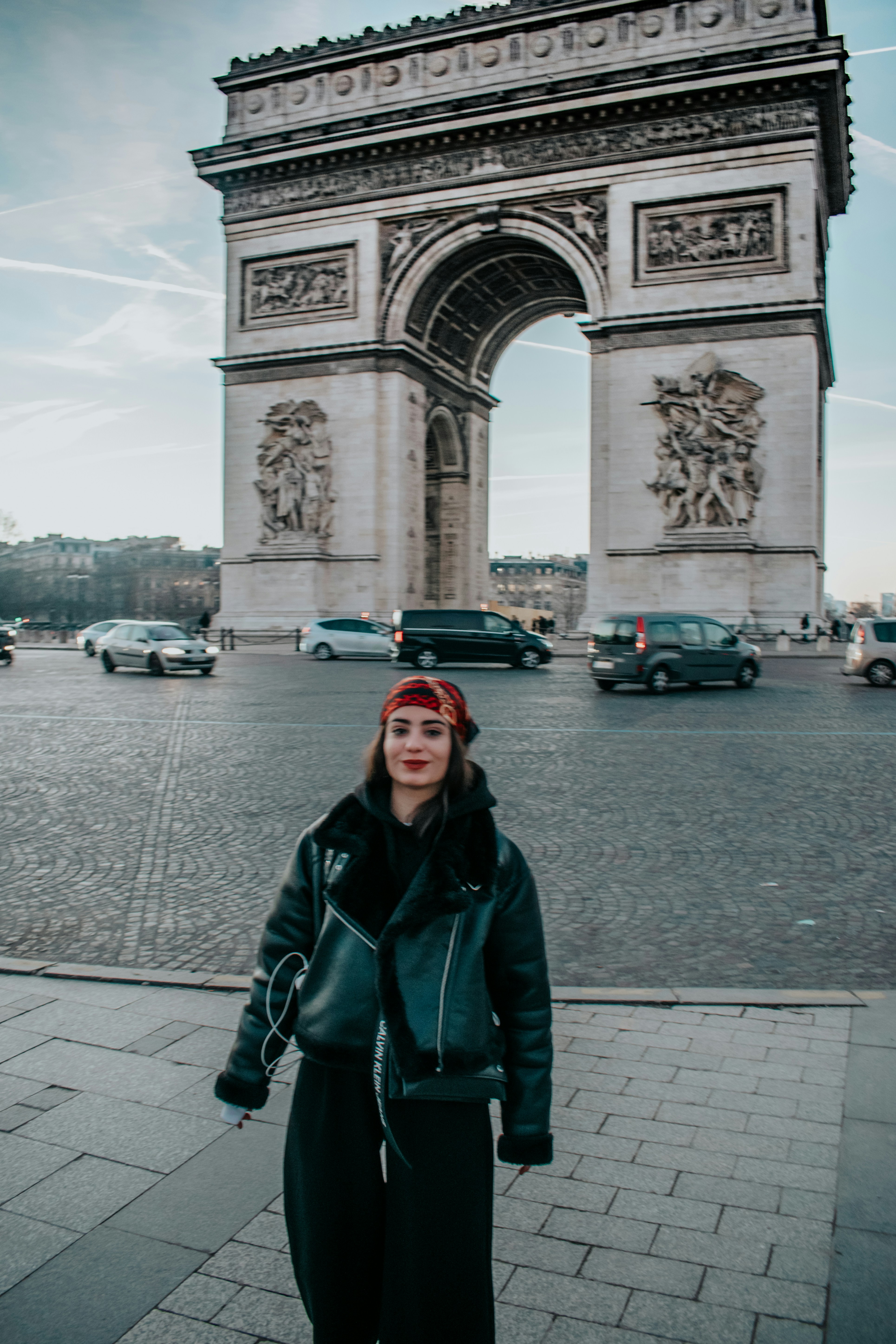 a woman standing in front of the arc of triumph