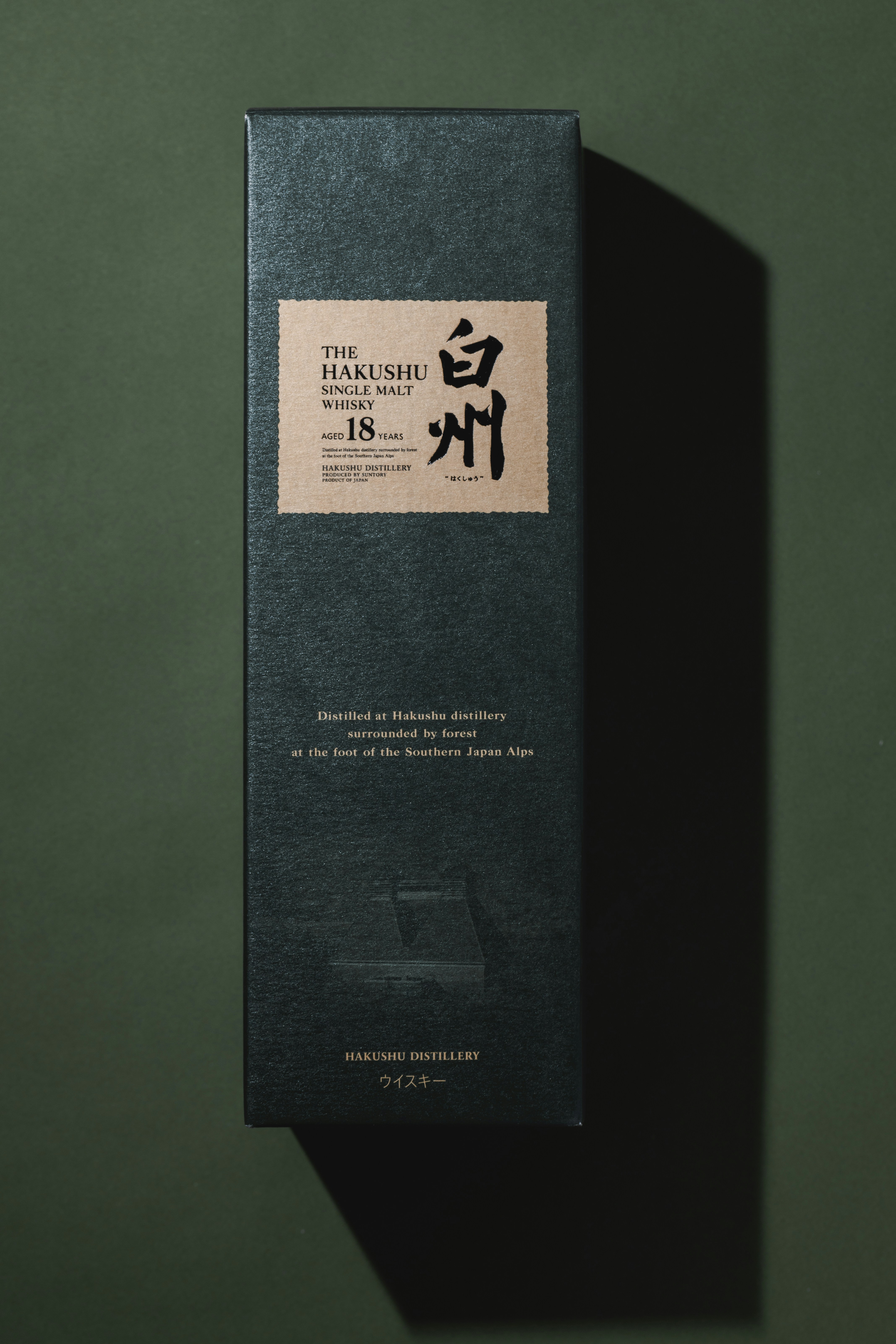 Elegant packaging of Hakushu 18-Year-Old Single Malt Whisky, featuring a minimalist design and earthy tones. The box highlights the whisky's origins at the foot of the Japanese Alps.