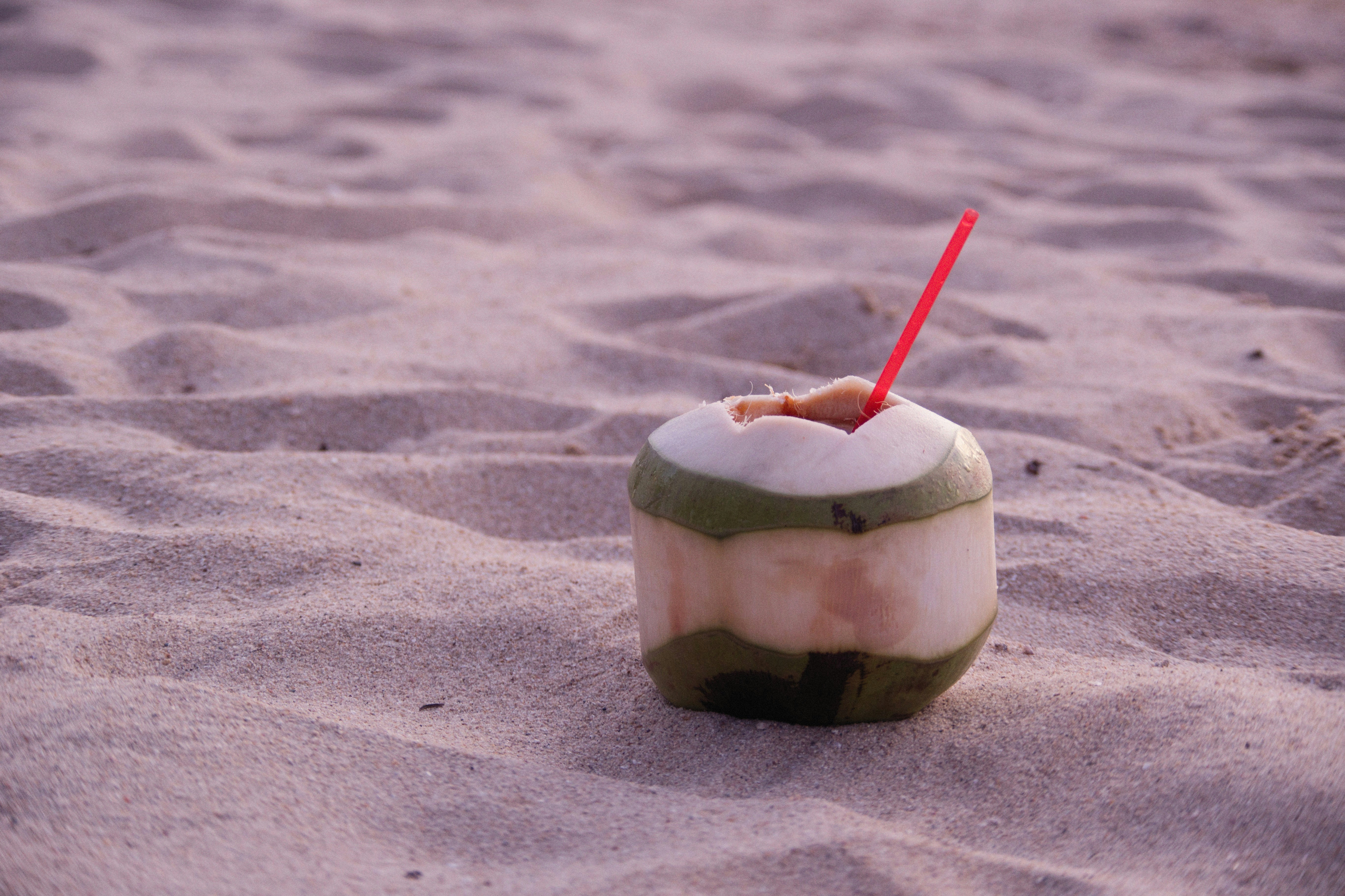A green and white drink sitting on top of a sandy beach photo – Free ...