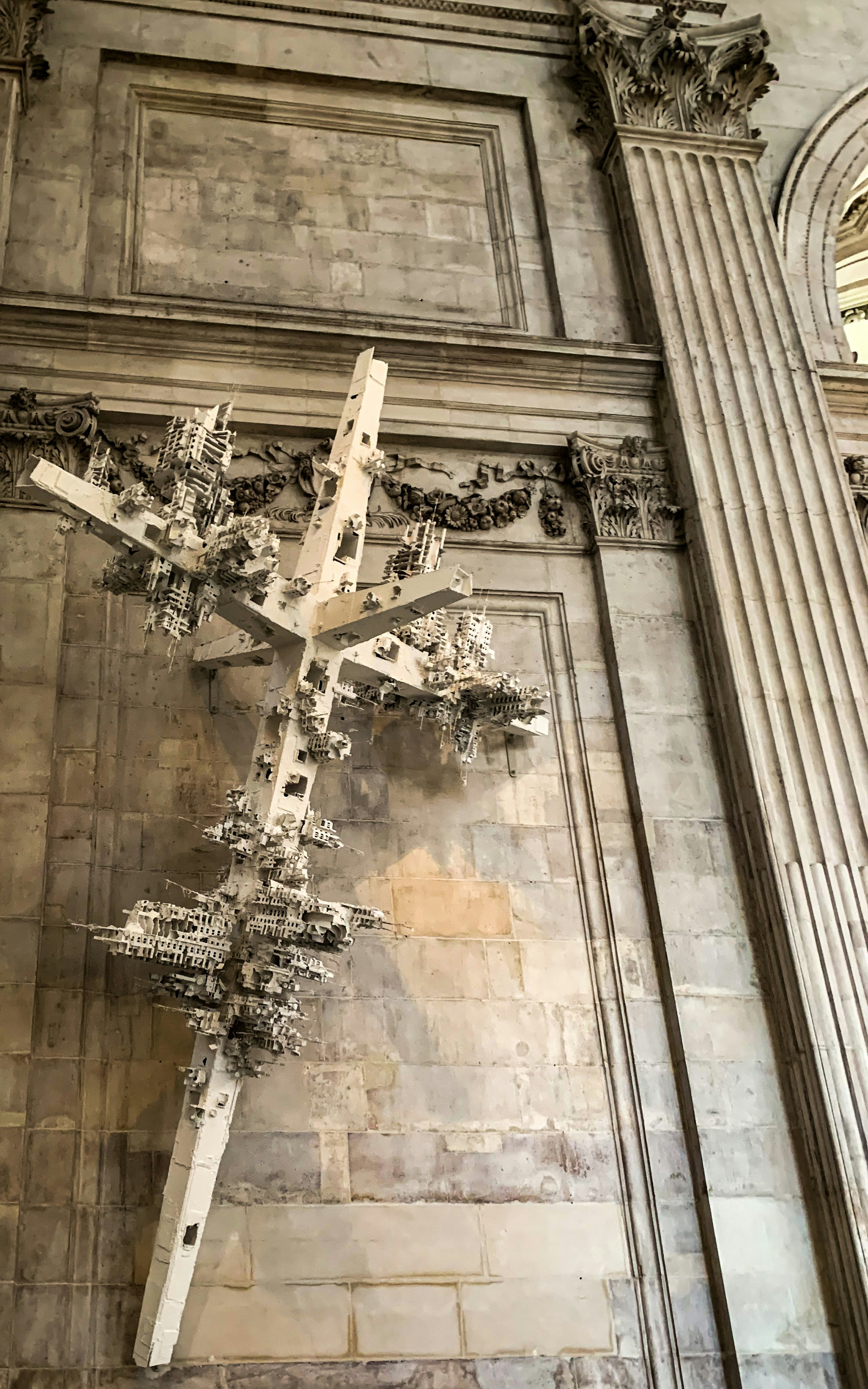 Miniature Worlds Adorn a Weathered Cross in a Silent Cathedral