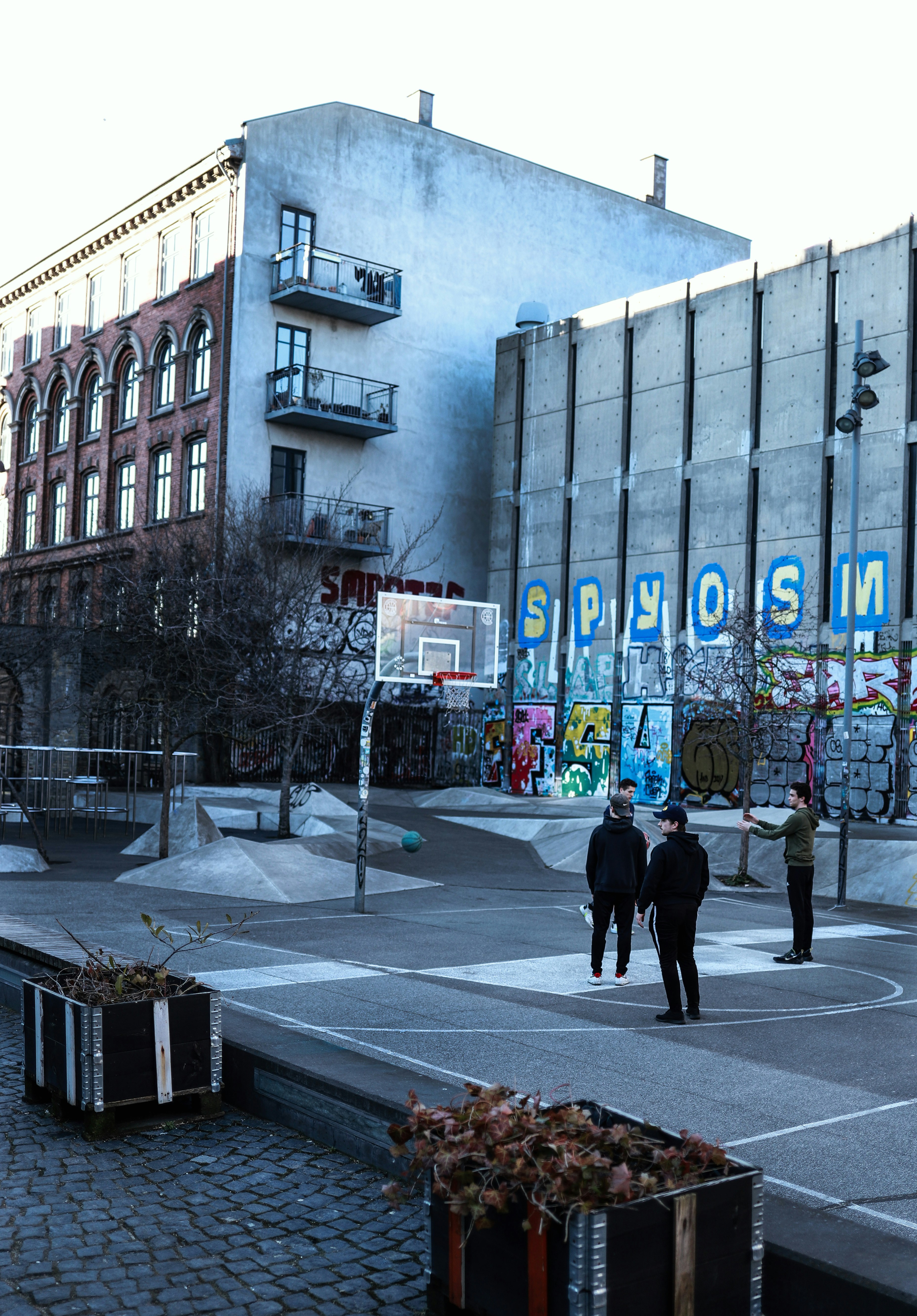 Graffiti Court: Urban Playfield Beneath Aged Brick and Blue Sky