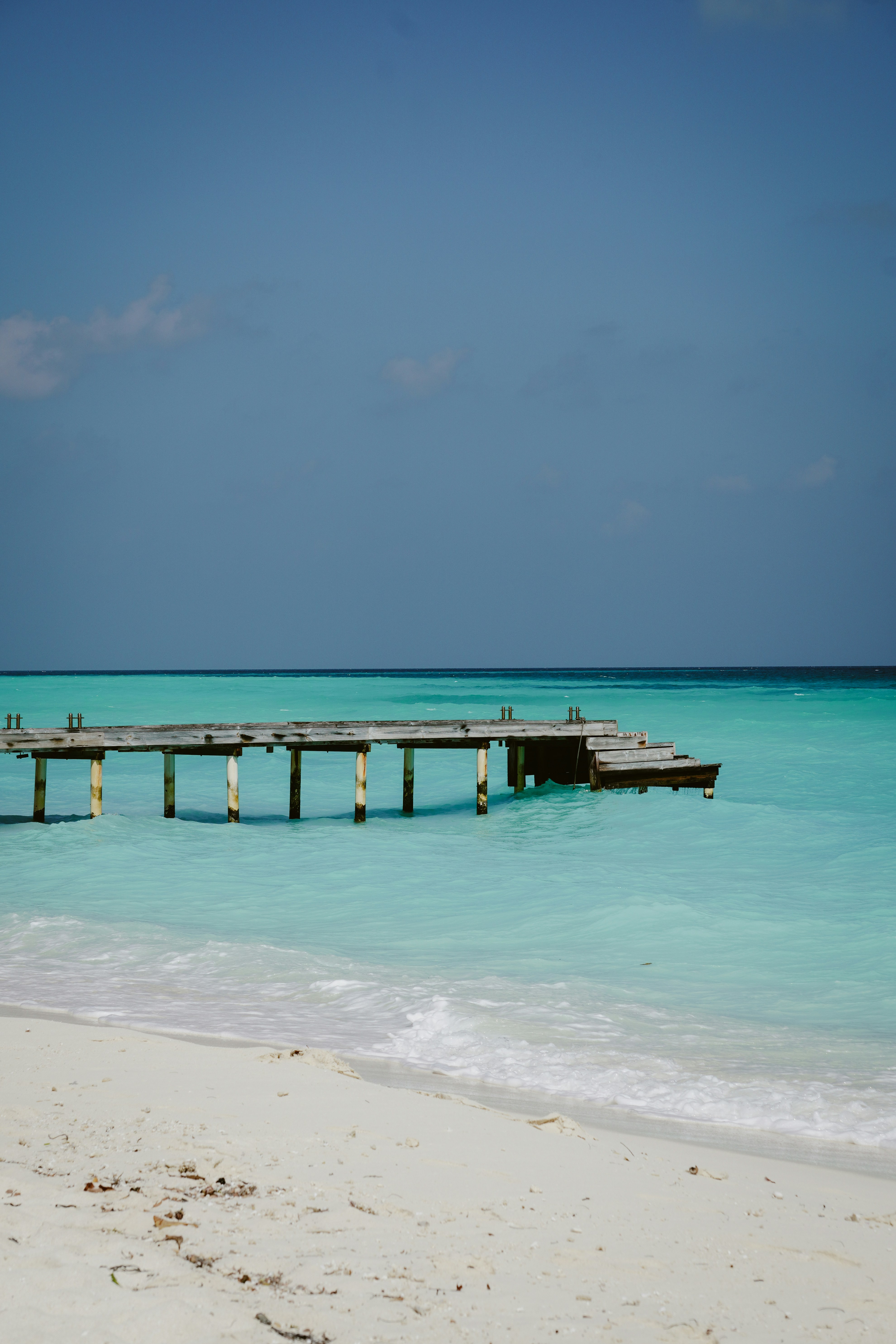 A long dock sitting on top of a sandy beach photo – Free Grey Image on ...