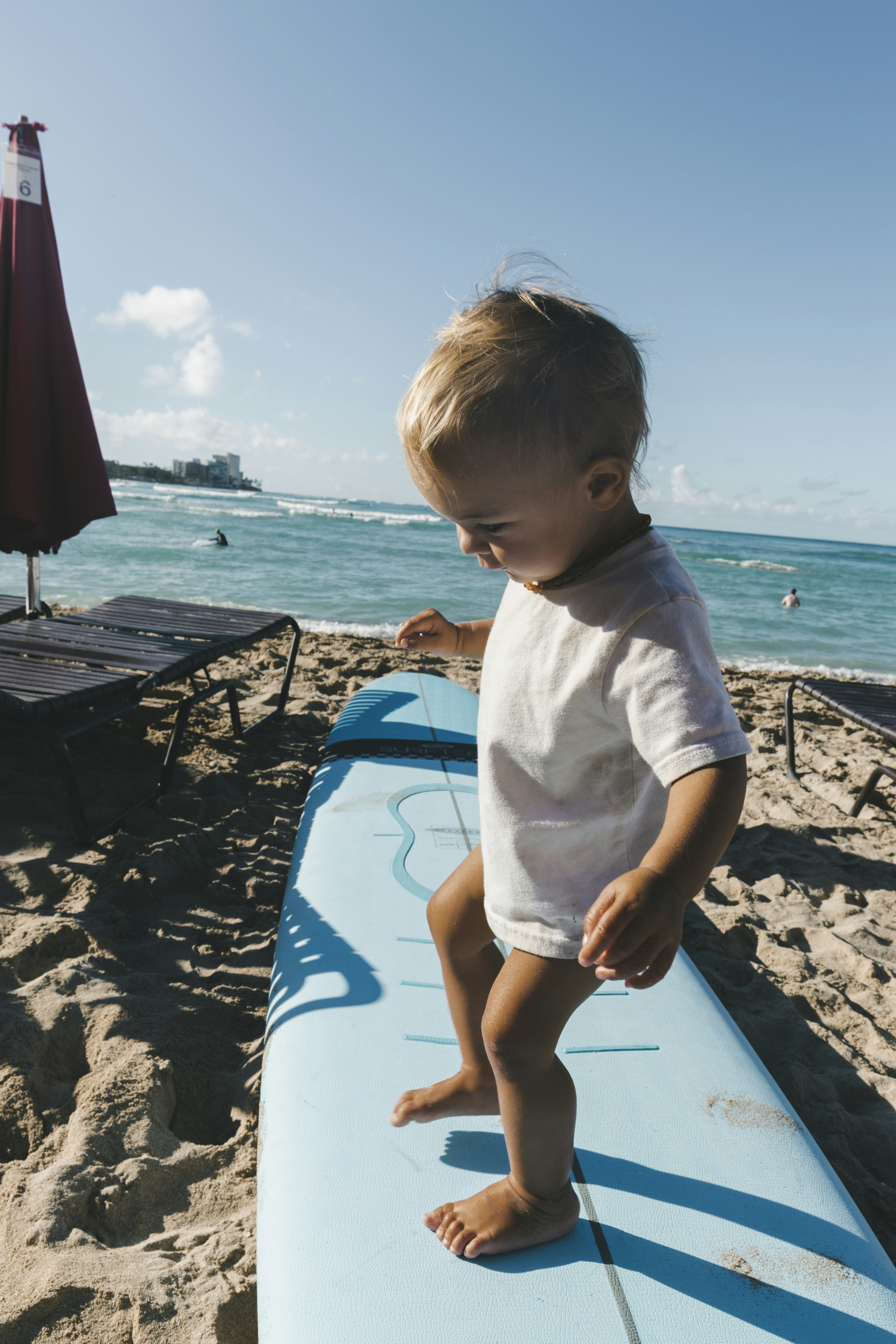 Foto Un bebé parado en una tabla de surf en la playa – Imagen Mar ...