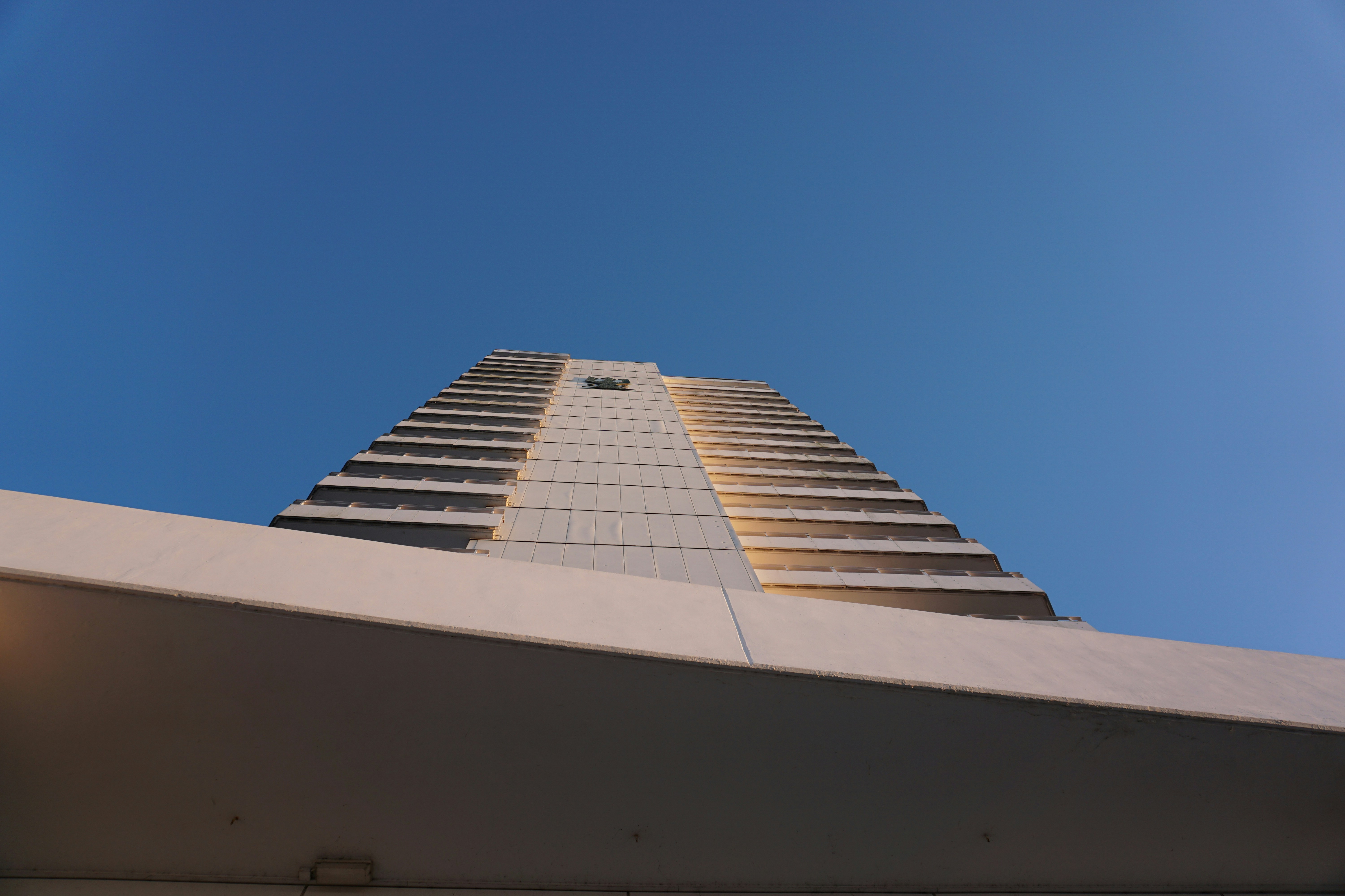 Tall building viewed from below against a clear blue sky.