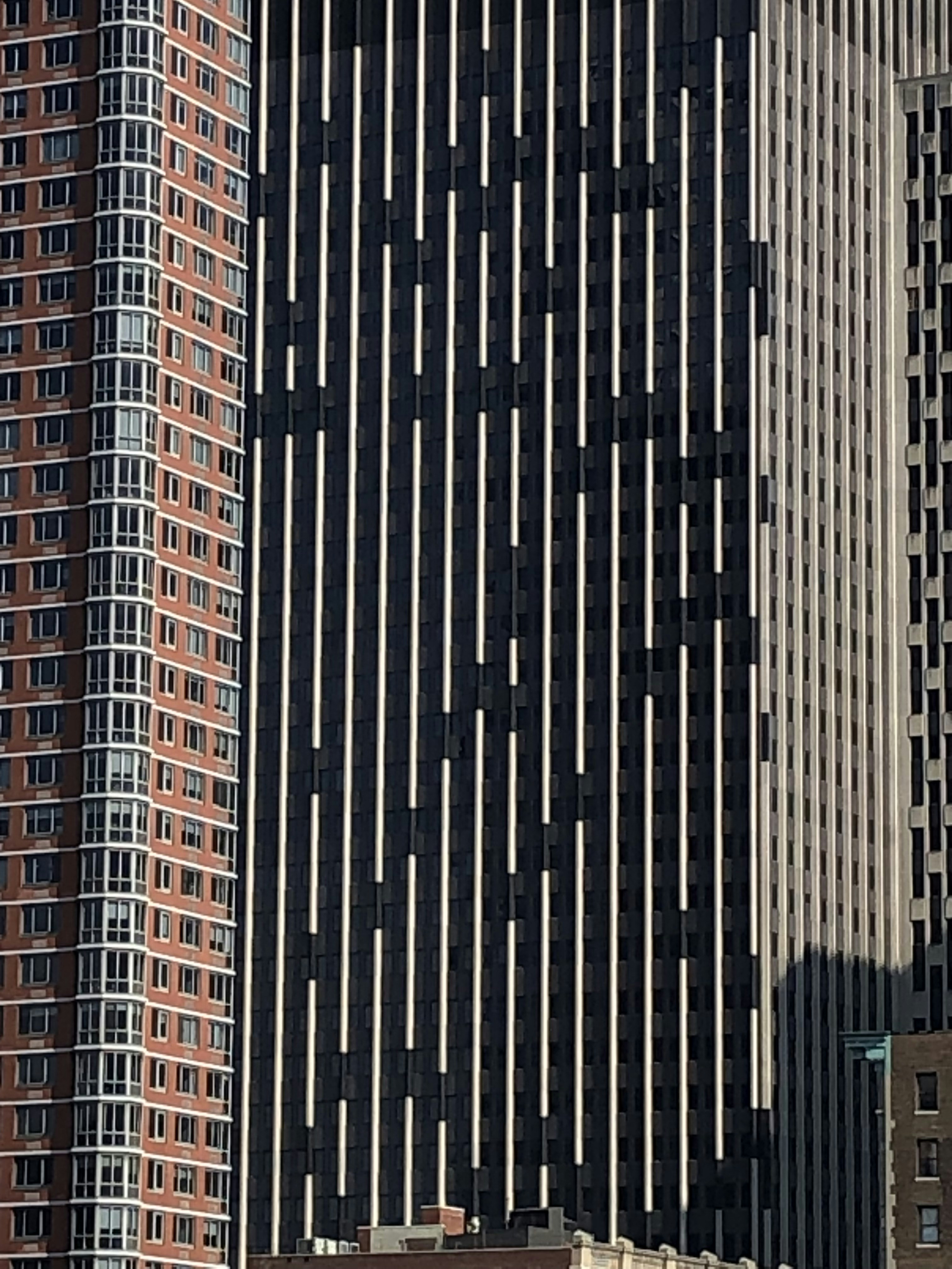 Close-up view of a modern urban landscape featuring patterned building facades that play with light and shadow.