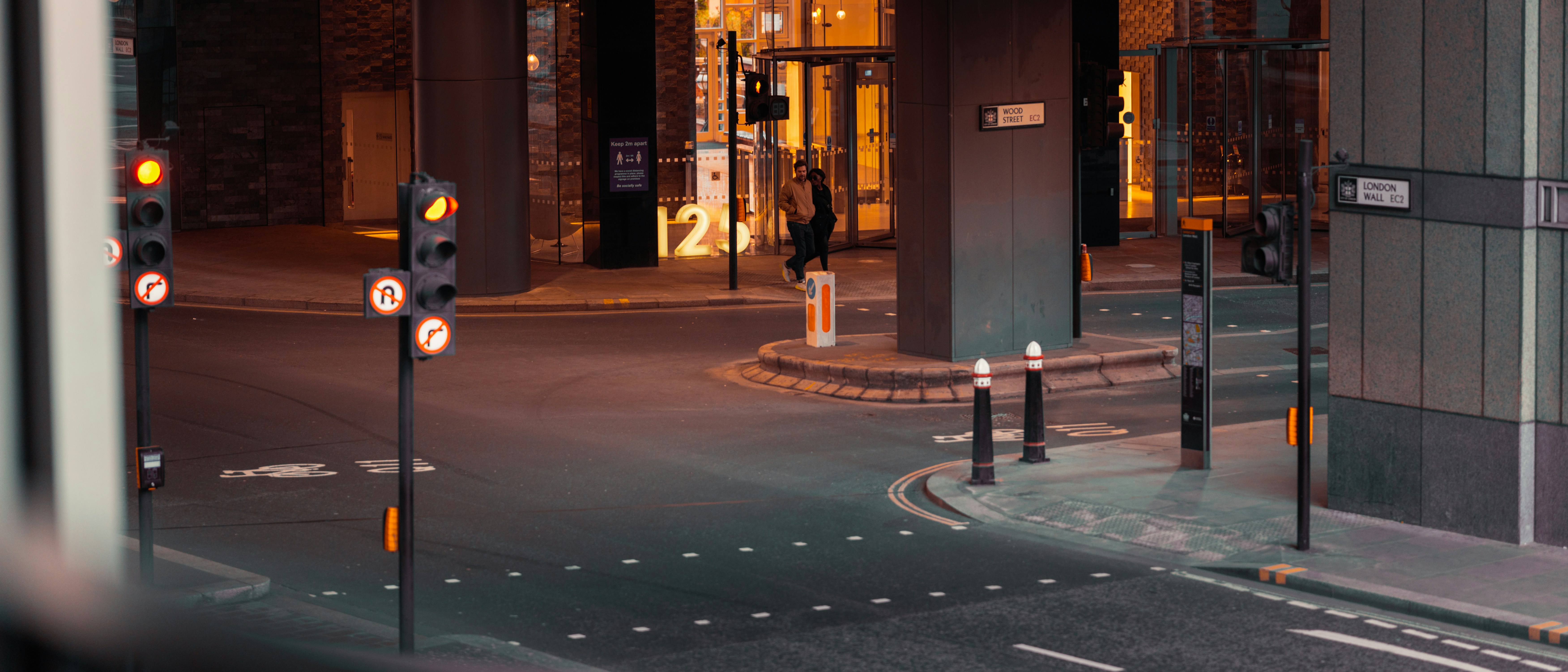 Empty city intersection with traffic lights glowing under dim evening light.