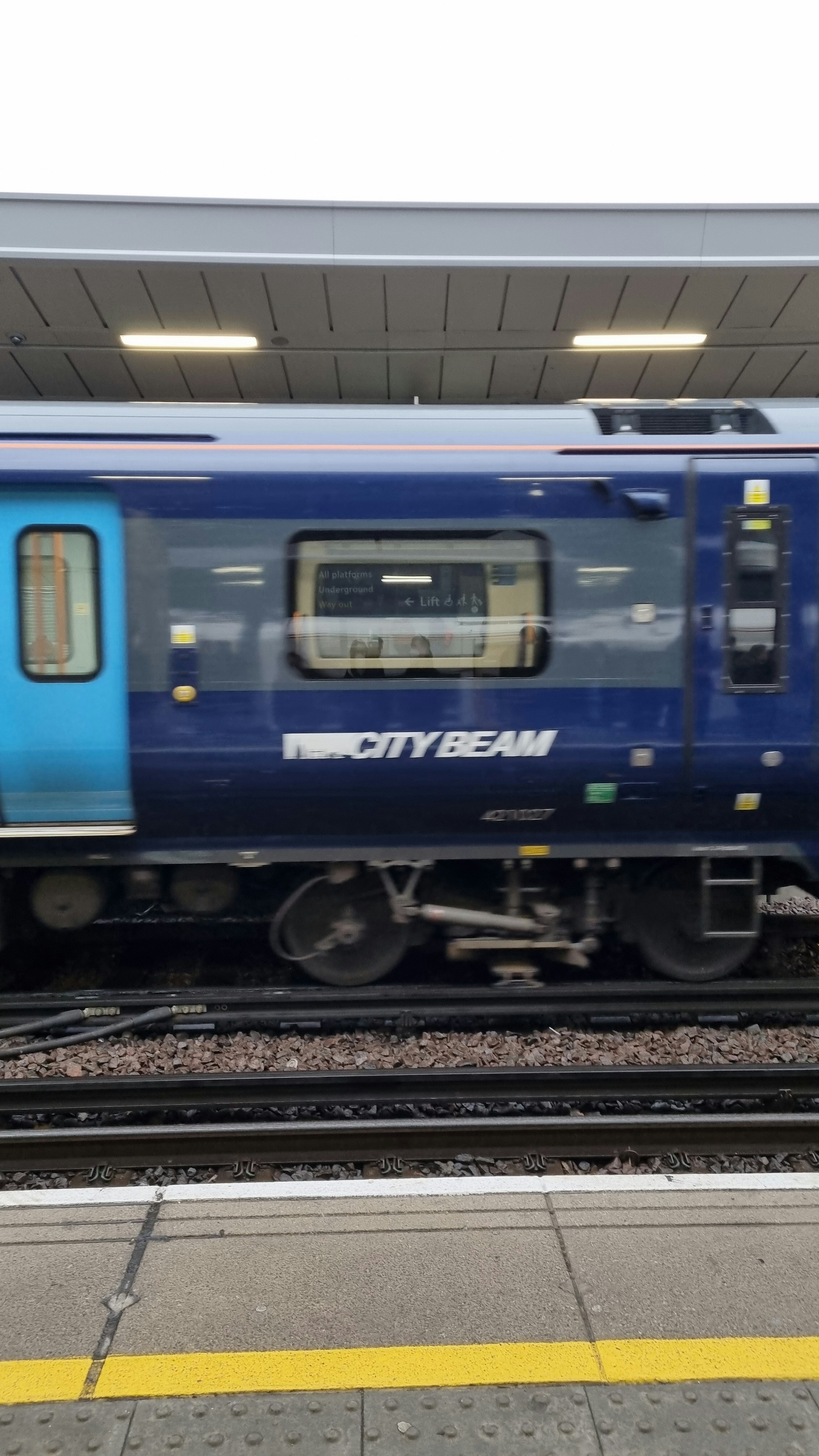 A blue train traveling down train tracks next to a platform photo ...