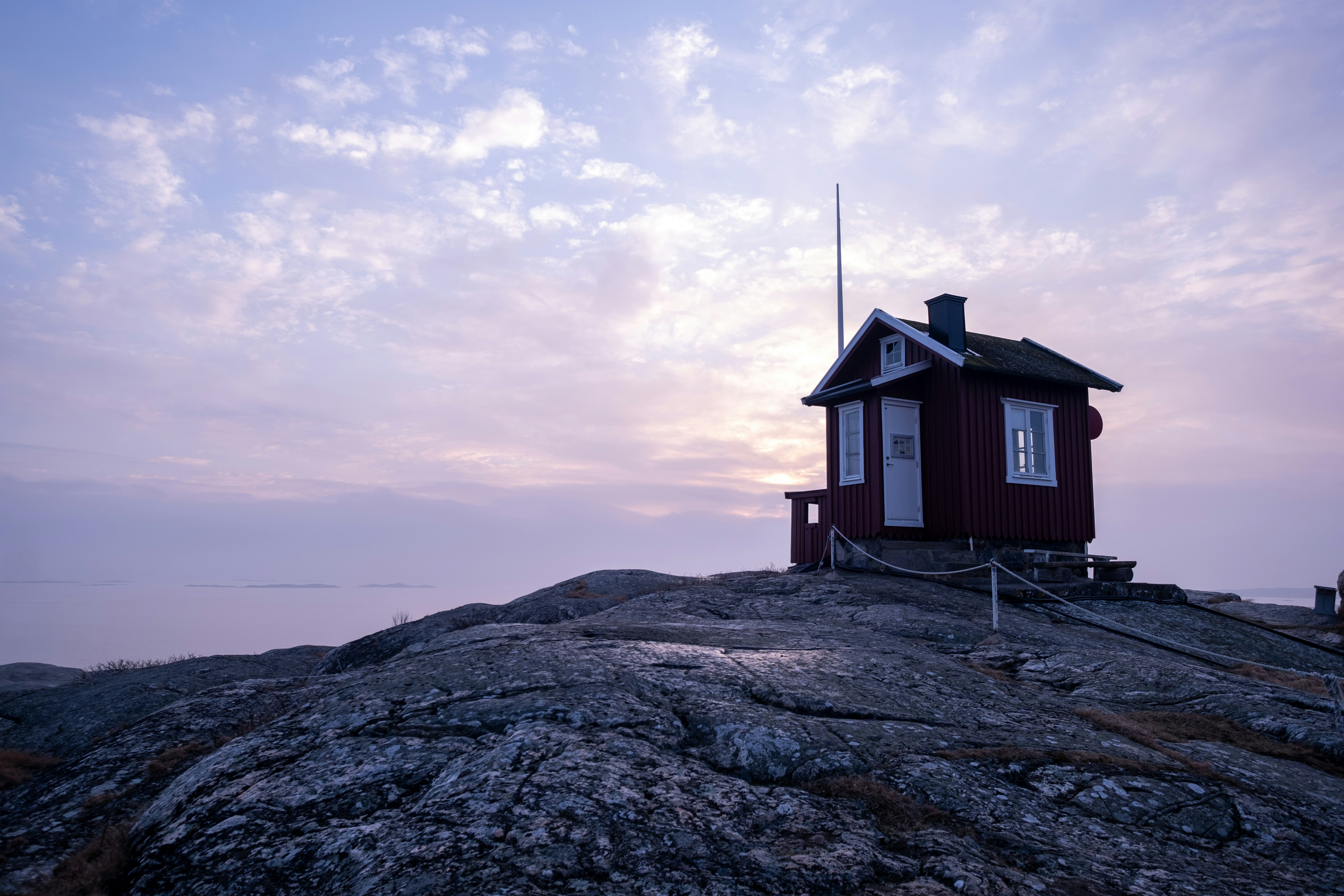 Lone Signal: A Red Cabin Standing Guard on Weathered Granite