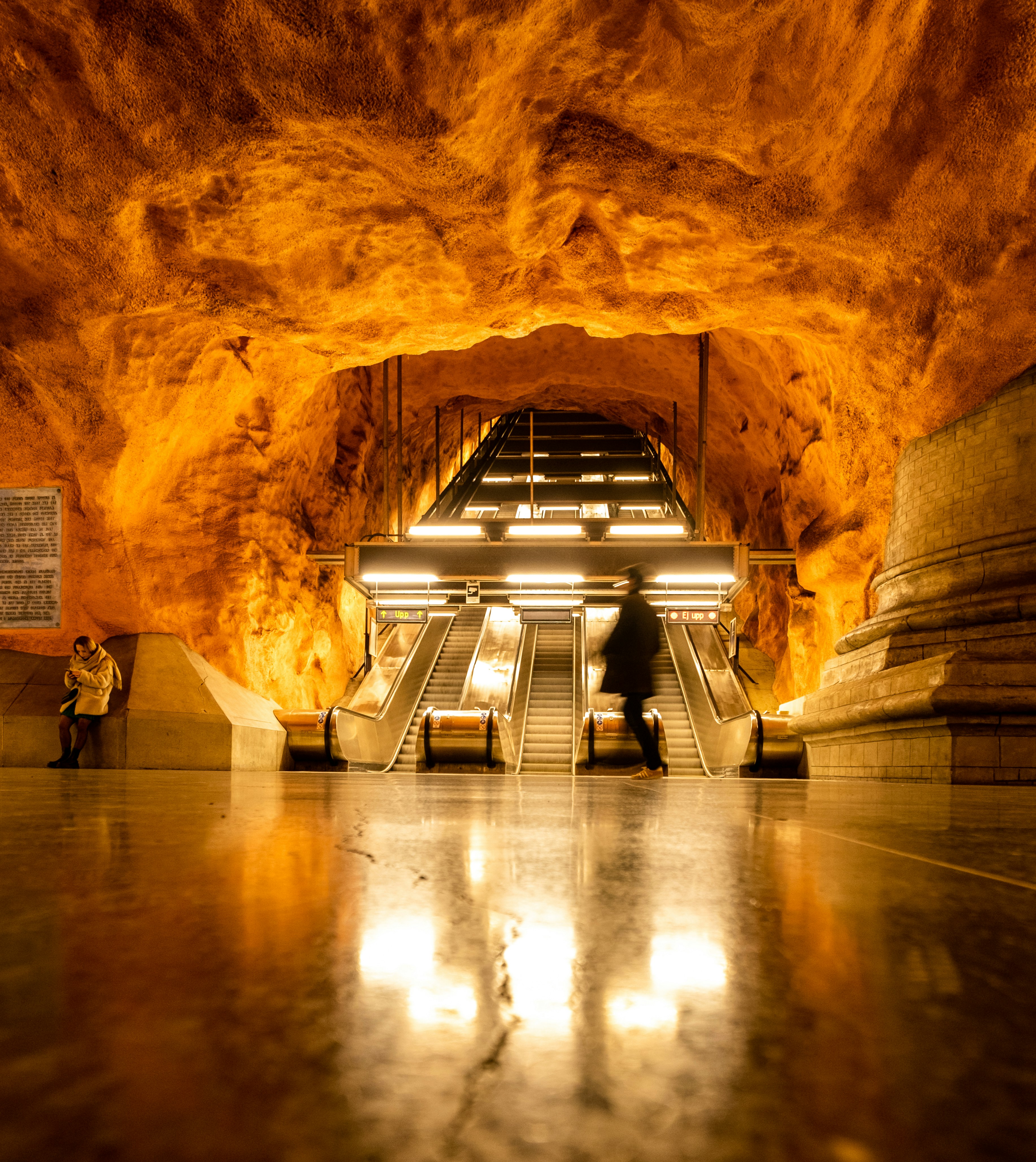 Underworld Lift: People and Lights in an Orange Cavern Station