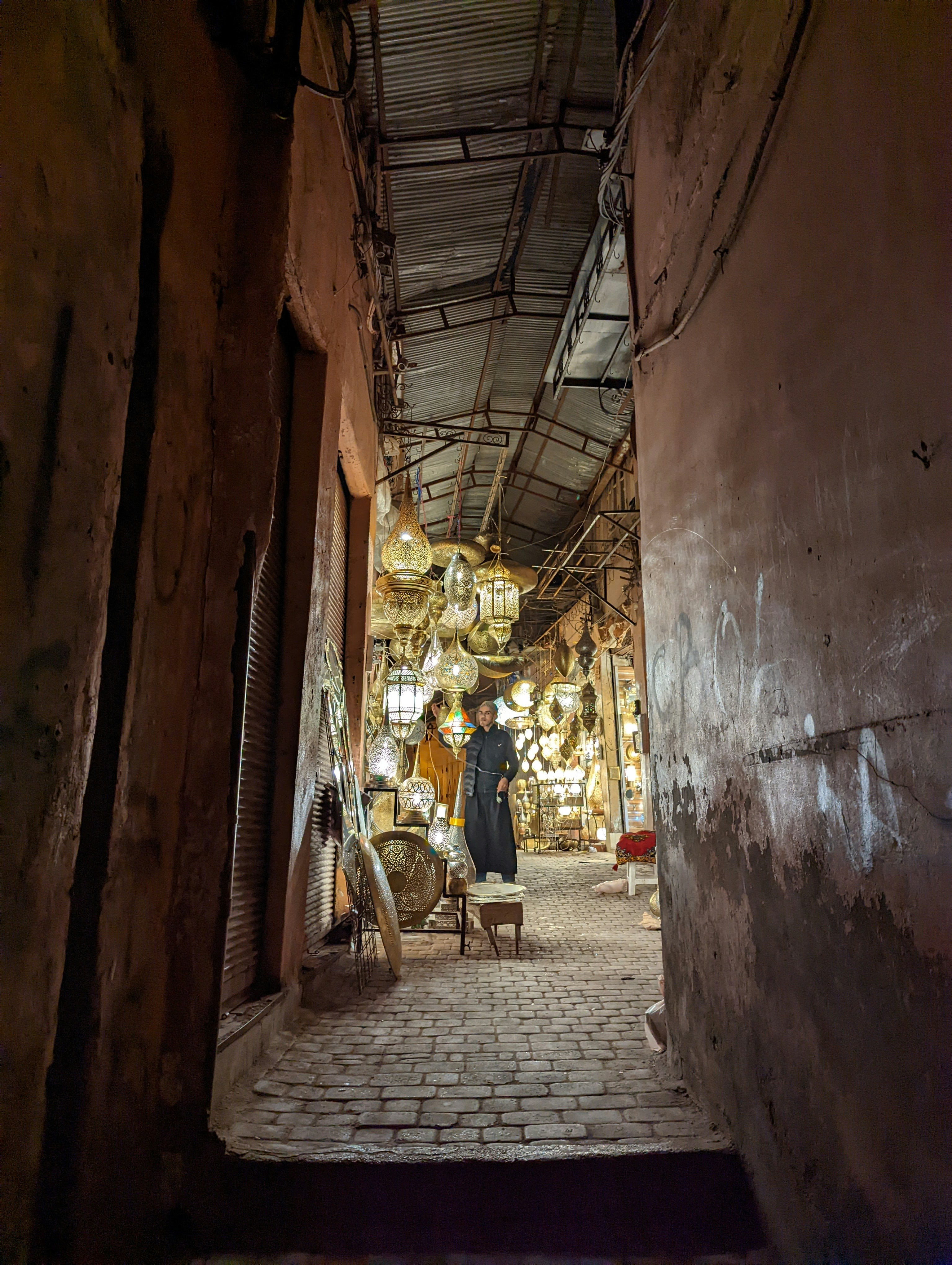 Narrow alley adorned with glowing lanterns, showcasing a figure in traditional attire amidst the warm ambiance. 
