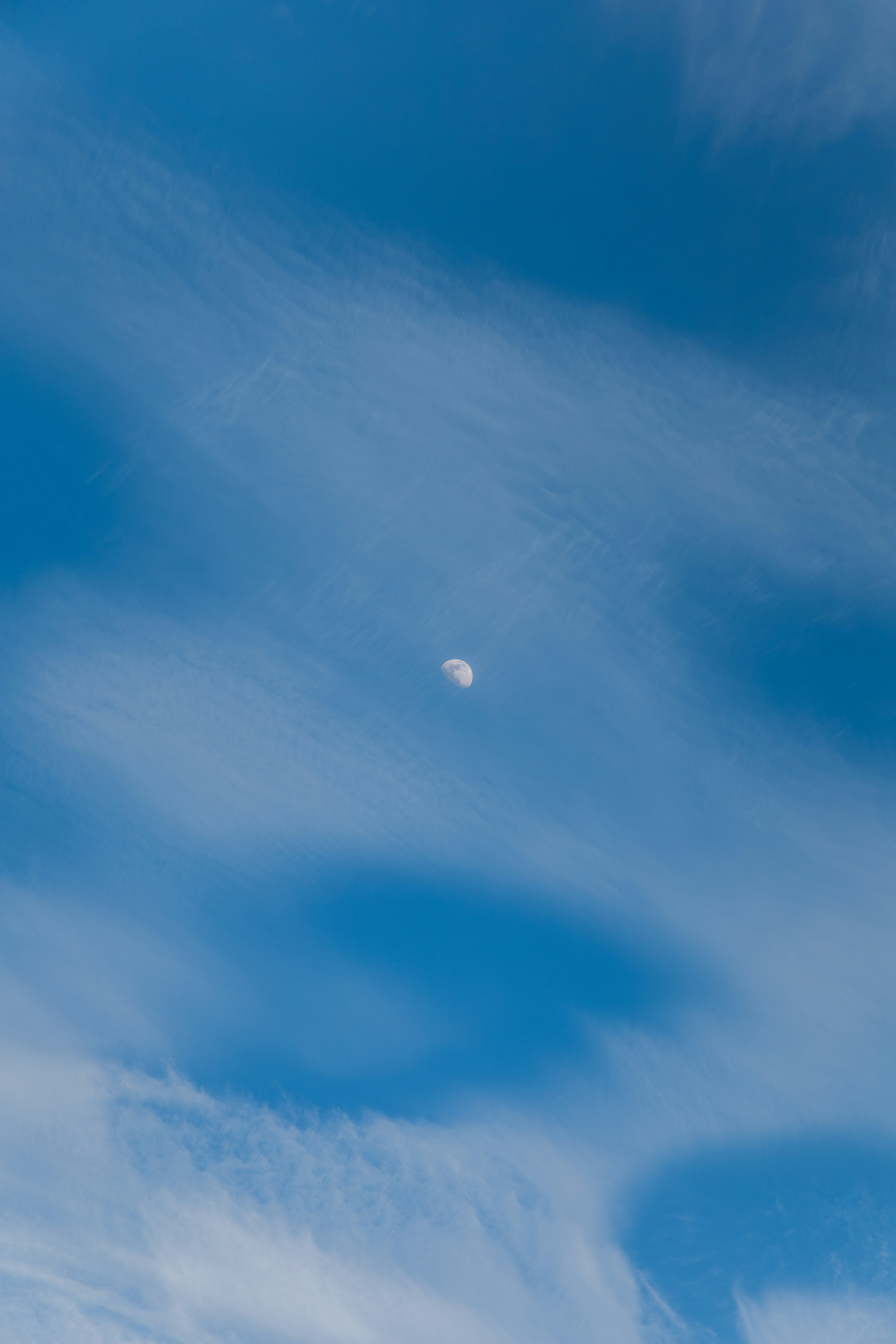 Hazy skies | a clear blue sky with clouds and a half moon