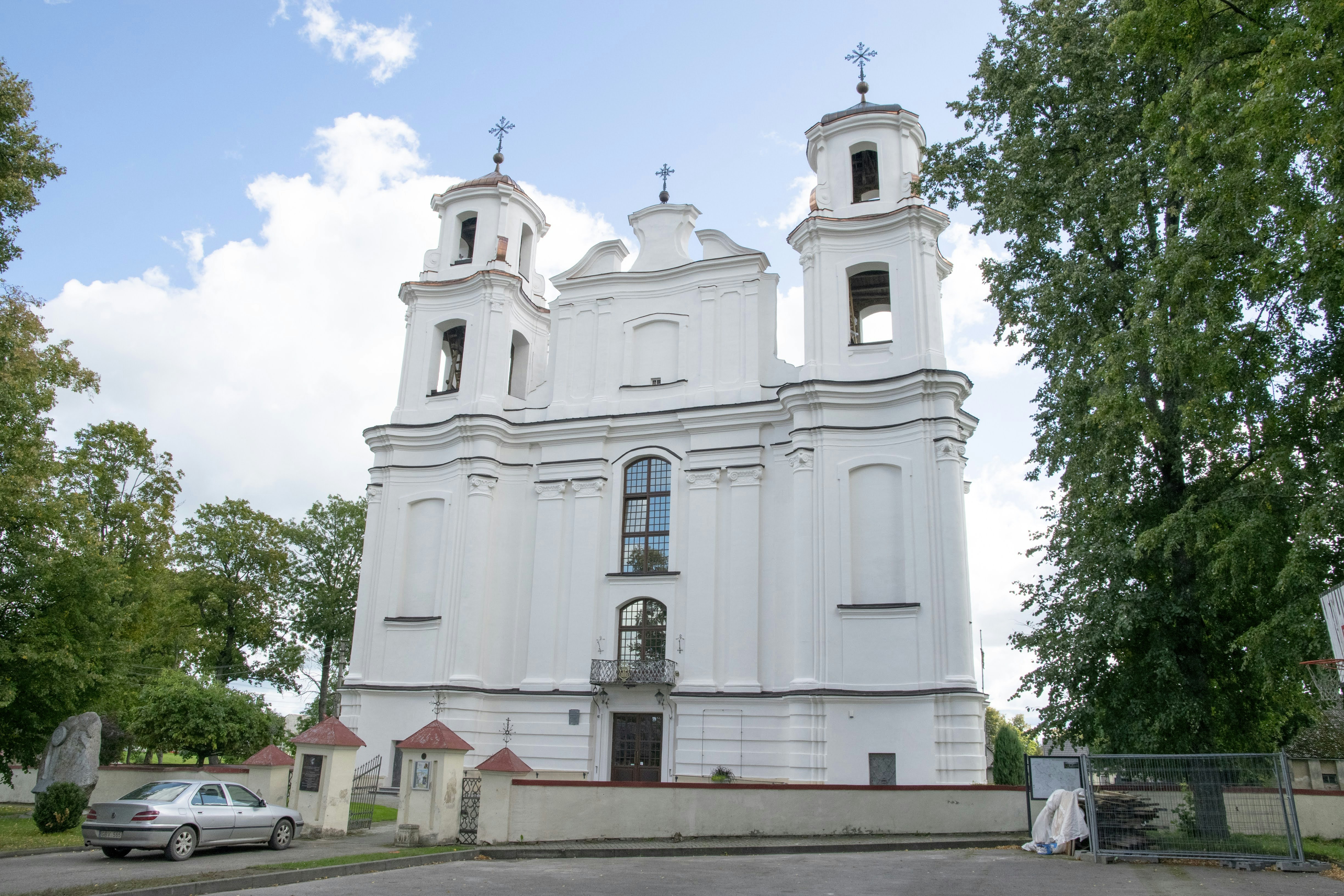 A large white church with two towers and a car parked in front of it ...