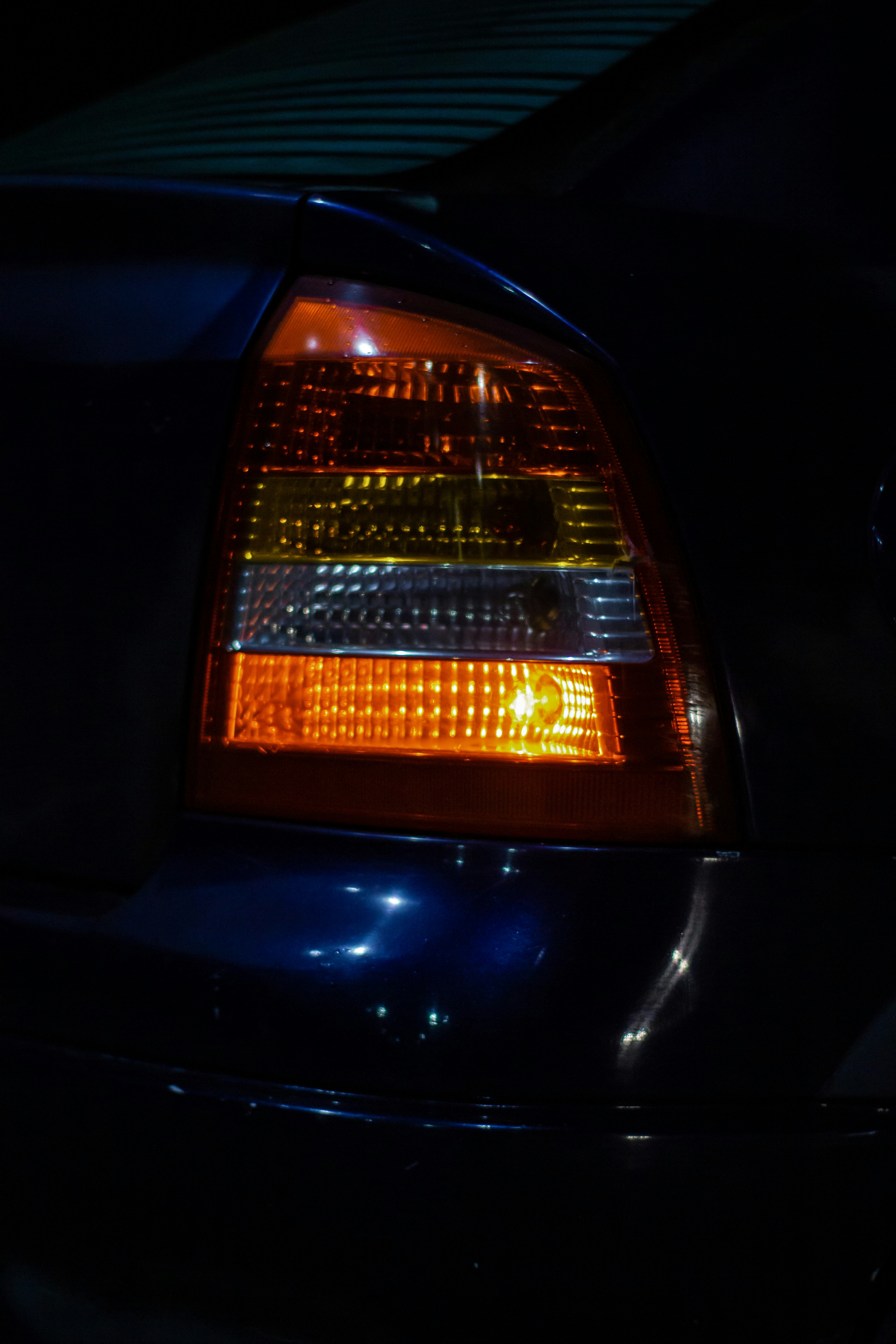 Close-up of a car's rear light cluster, showcasing the vibrant orange and white indicators against a dark backdrop.