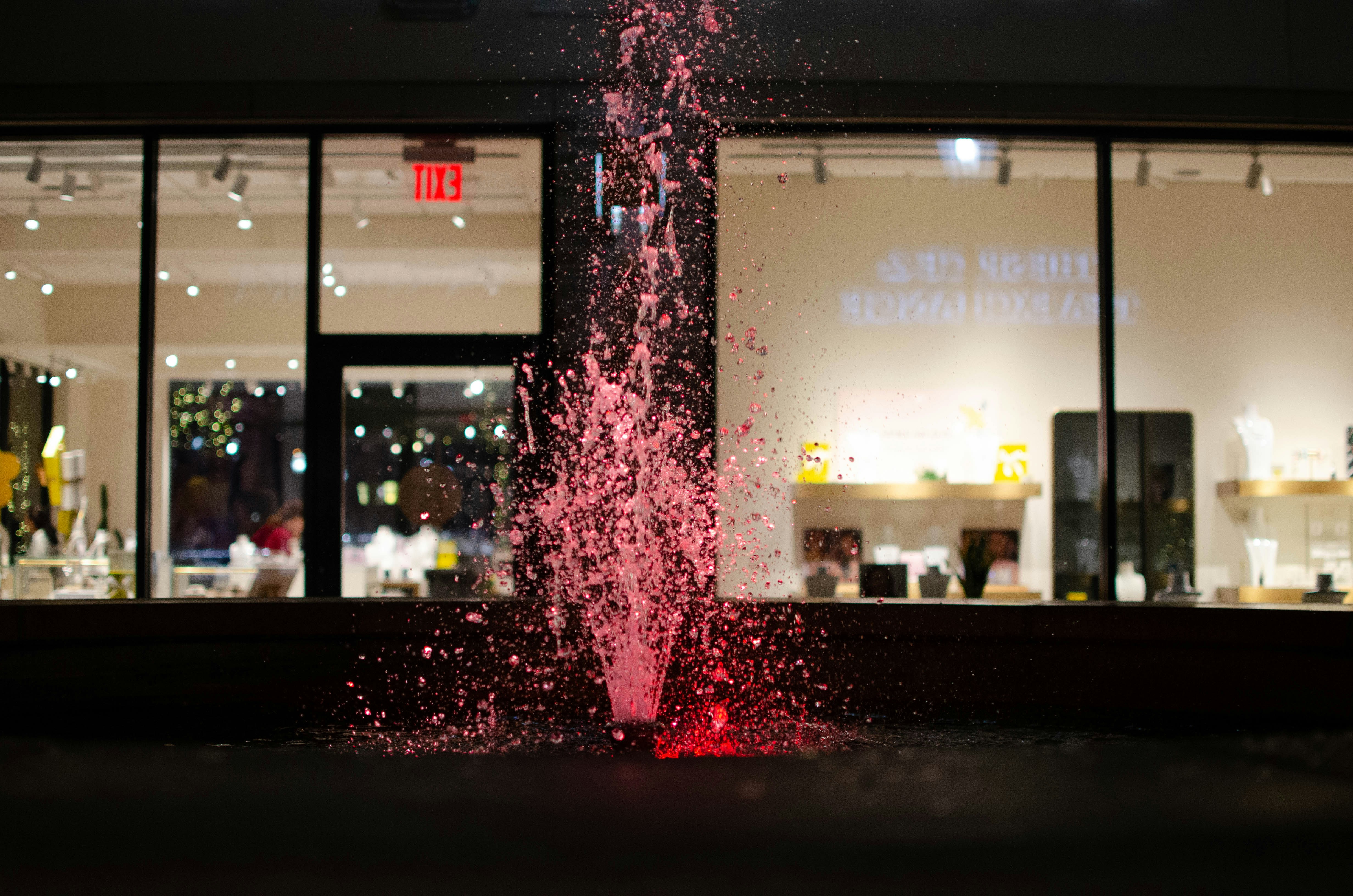 A red fountain spewing out water in front of a store photo – Free Red ...