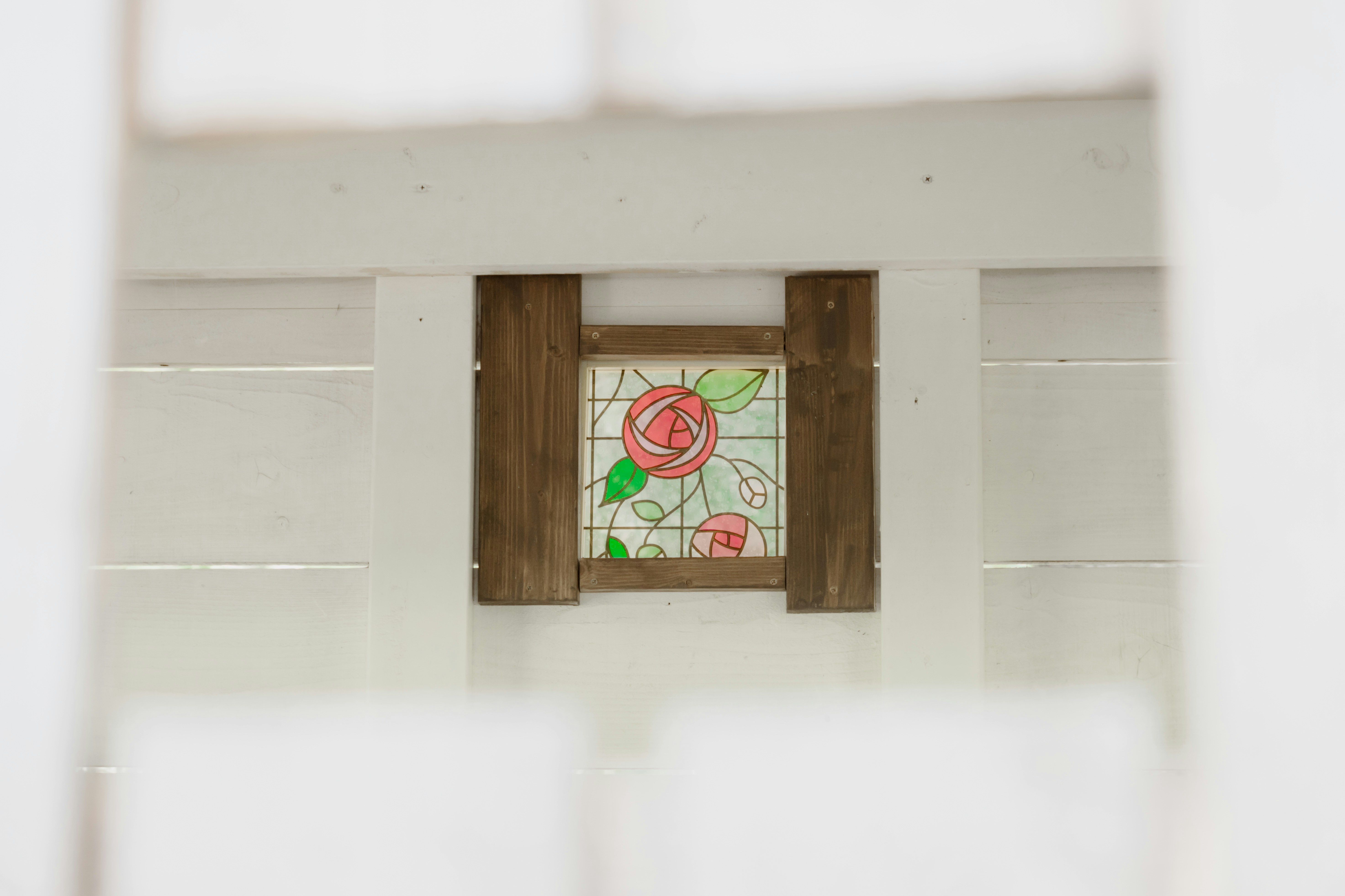 Hidden Rose Window Framed by Weathered Wood and White Walls