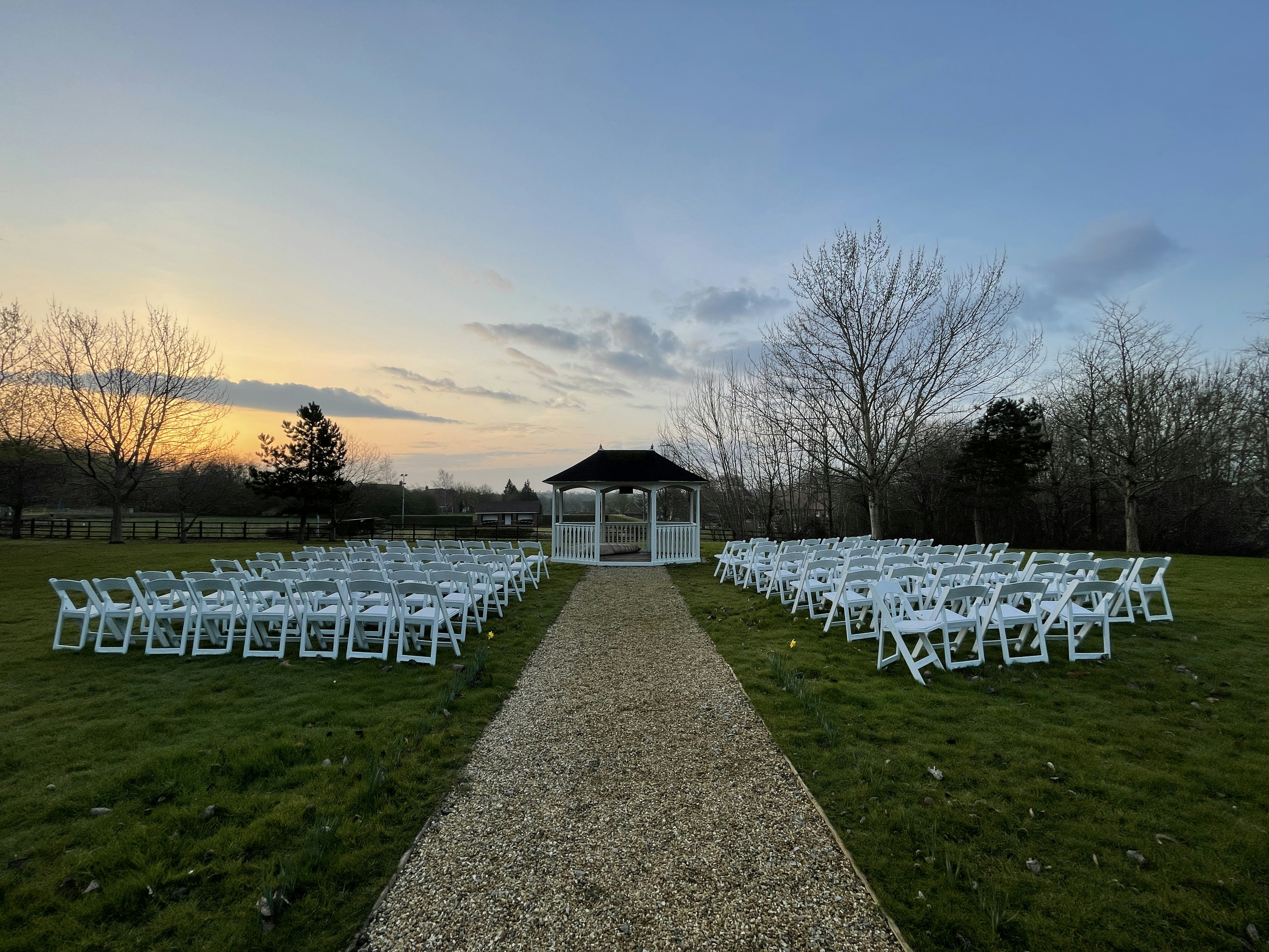 a set of white chairs sitting on top of a lush green field