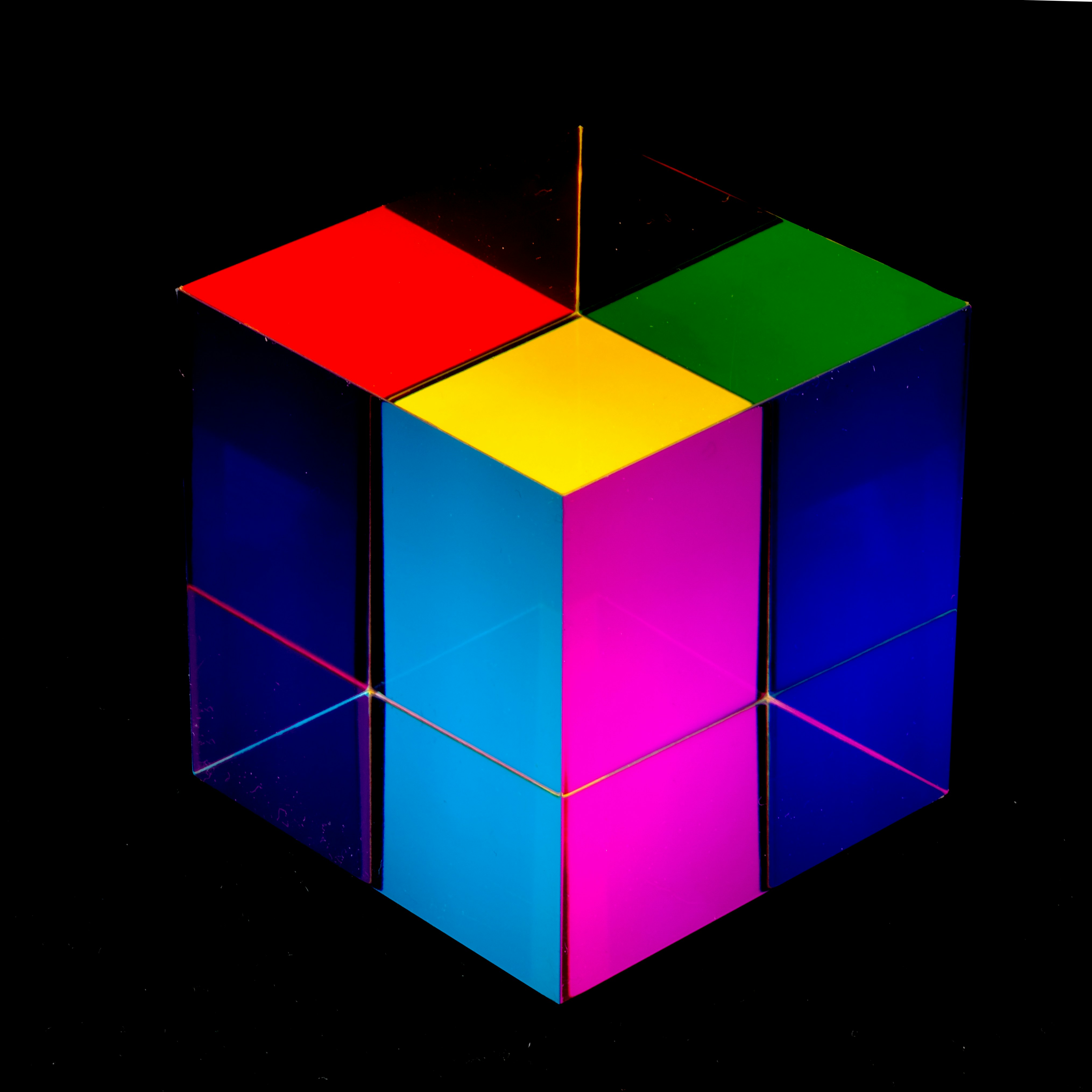 Multicolored cube reflecting vibrant hues against a black background.