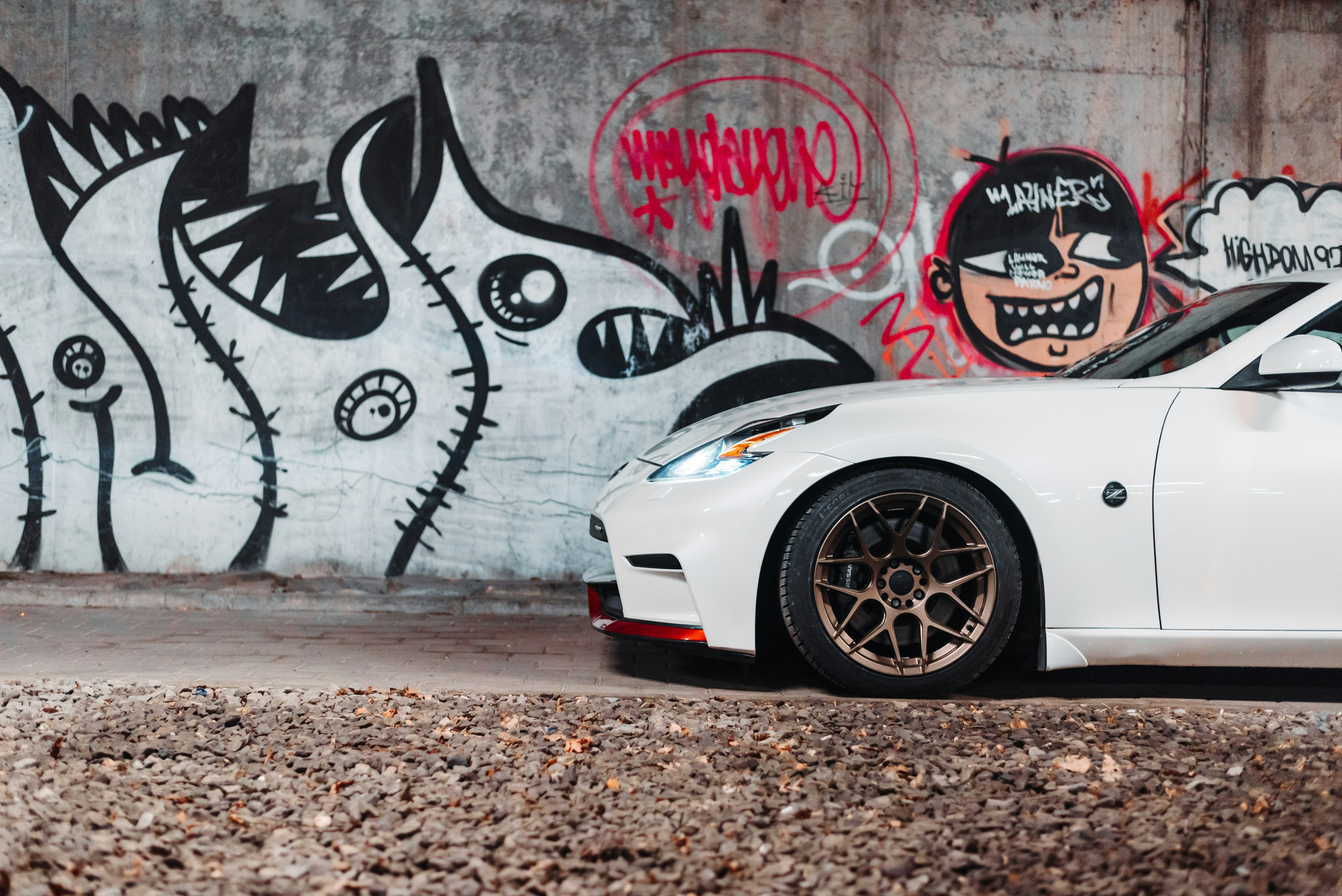 A white sports car parked in front of a graffiti covered wall photo ...