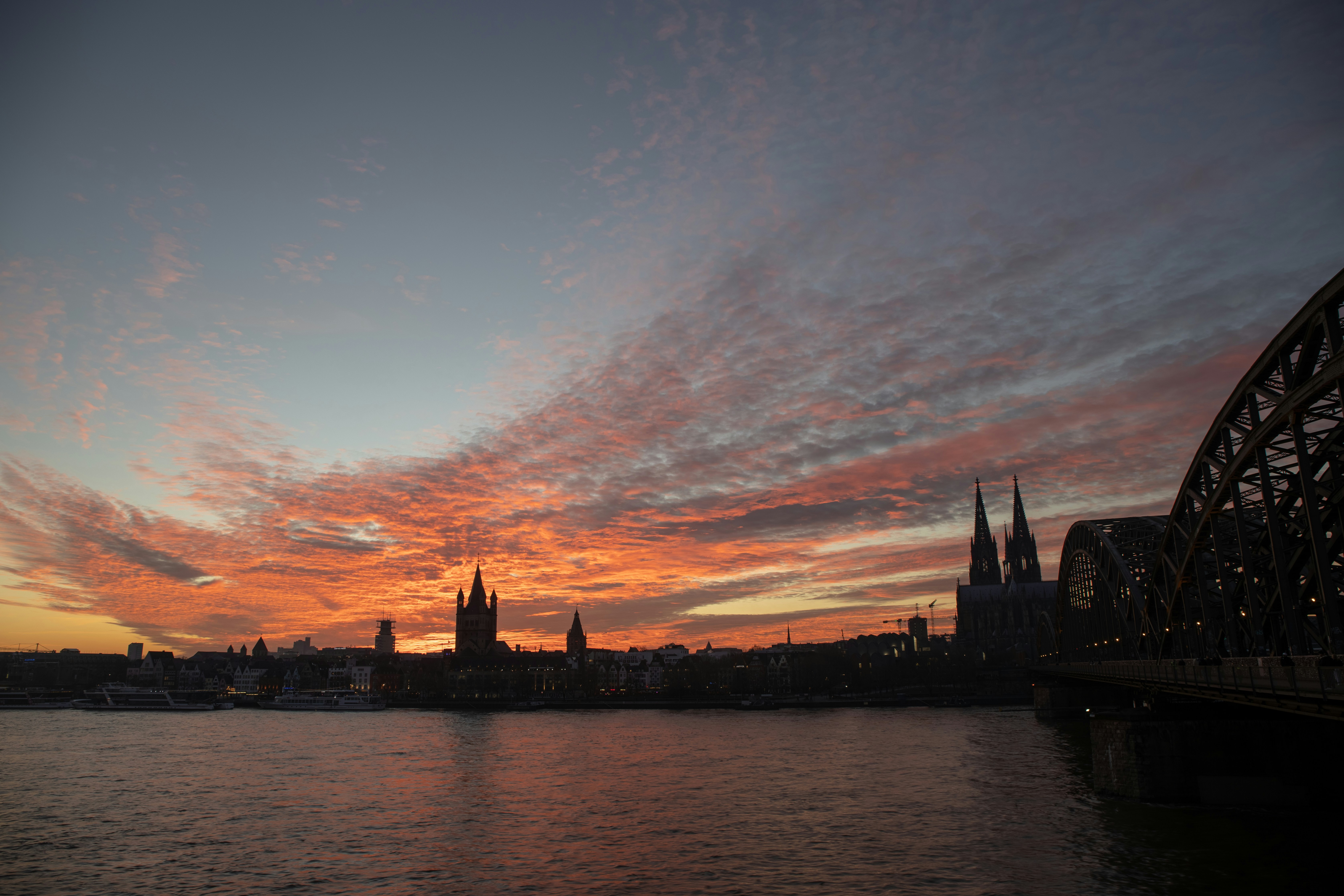 Dusk over the Rhine: Fiery Clouds Framing a Cathedral Silhouette and Arched Bridge
