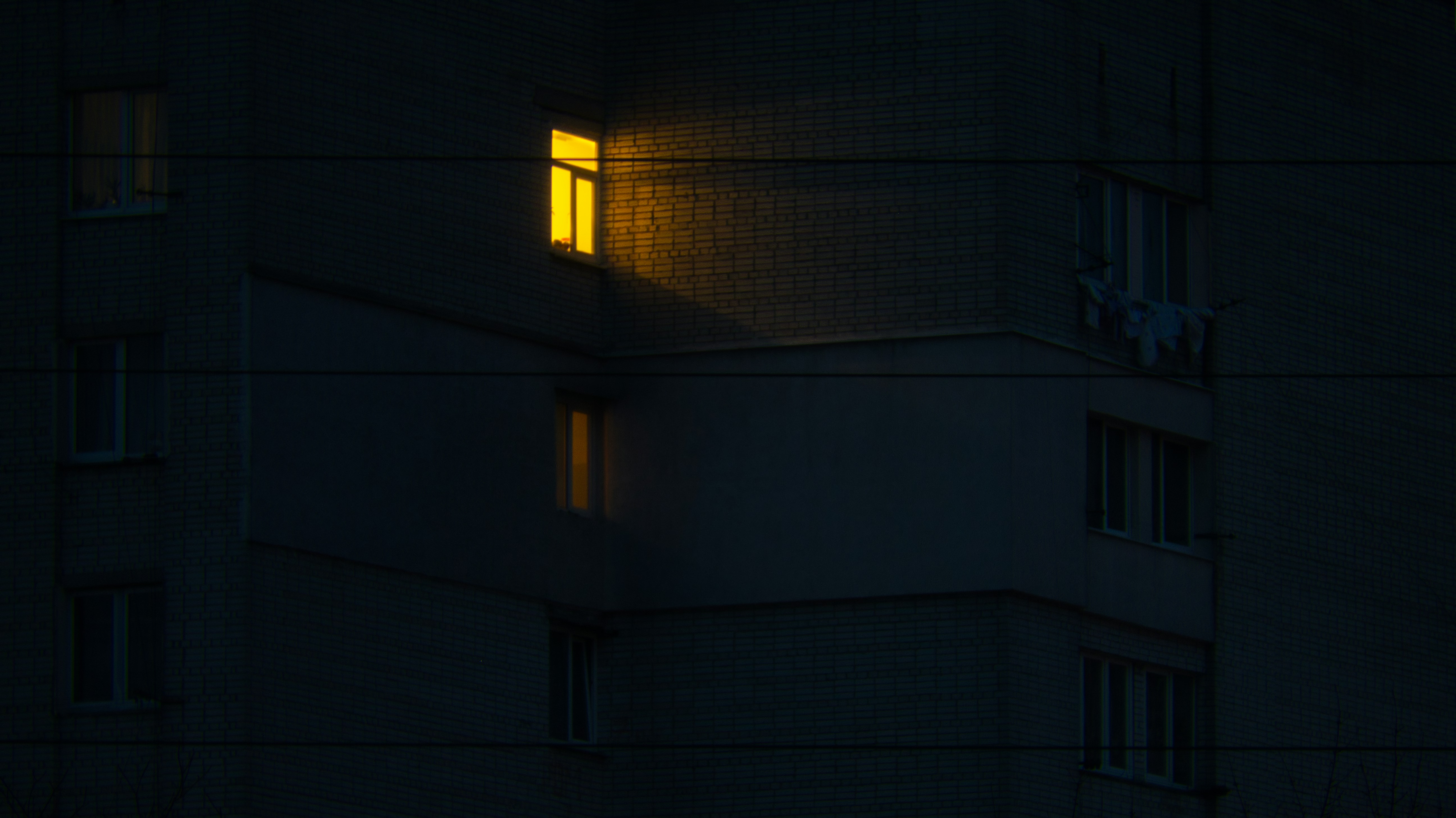 A building with a window lit up at night photo – Free Wallpapers Image ...