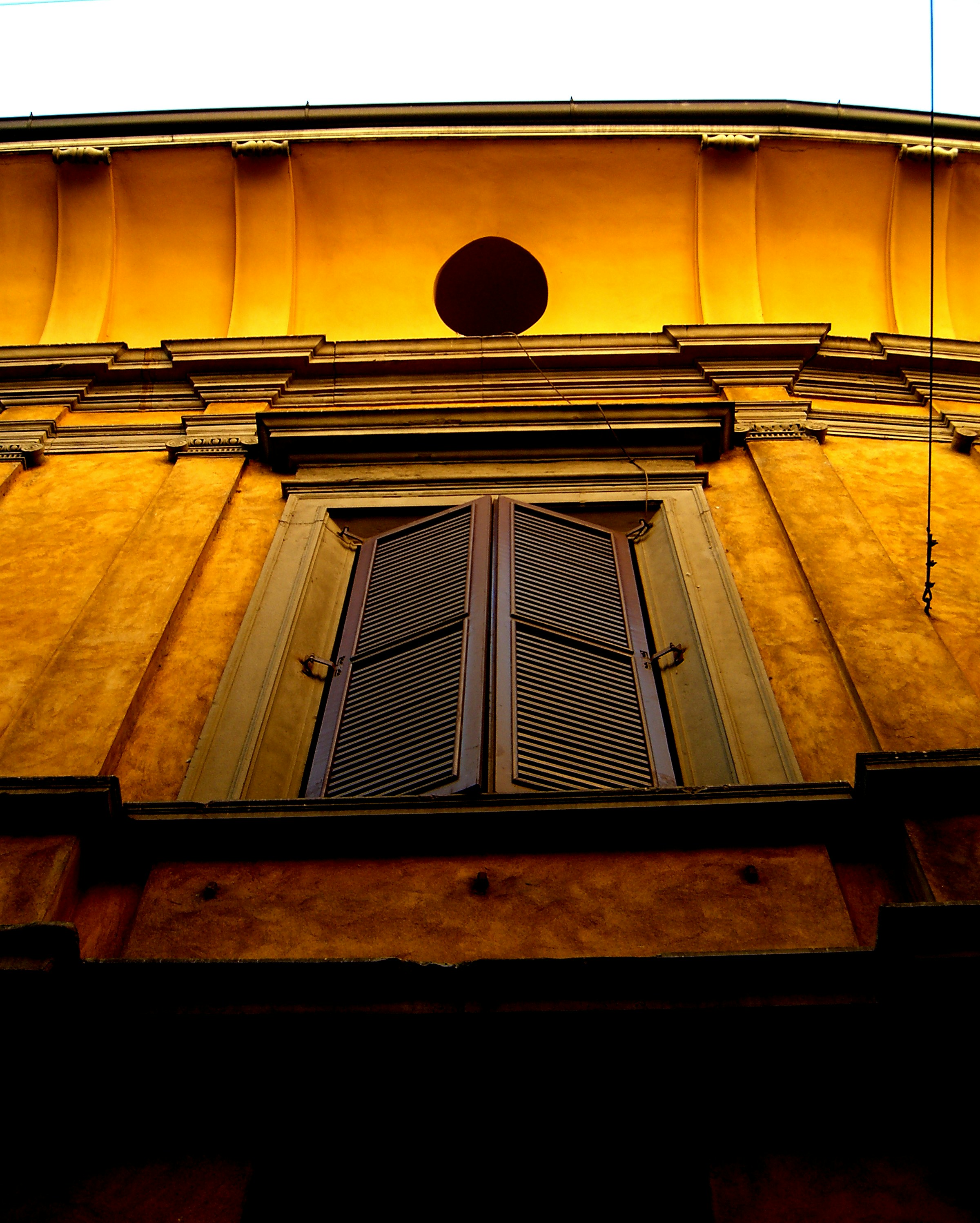 Ochre Facade Under a Circular Vent: A Low-Angle Architectural Portrait