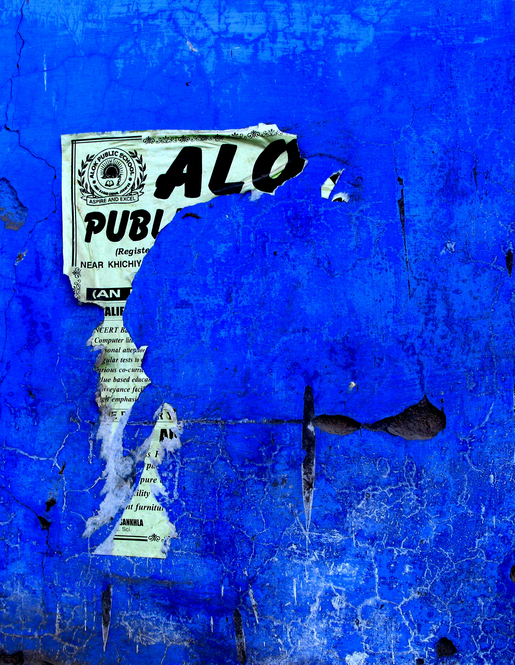 Neon Blue Decay: Torn Poster Fragments on a Weathered Wall