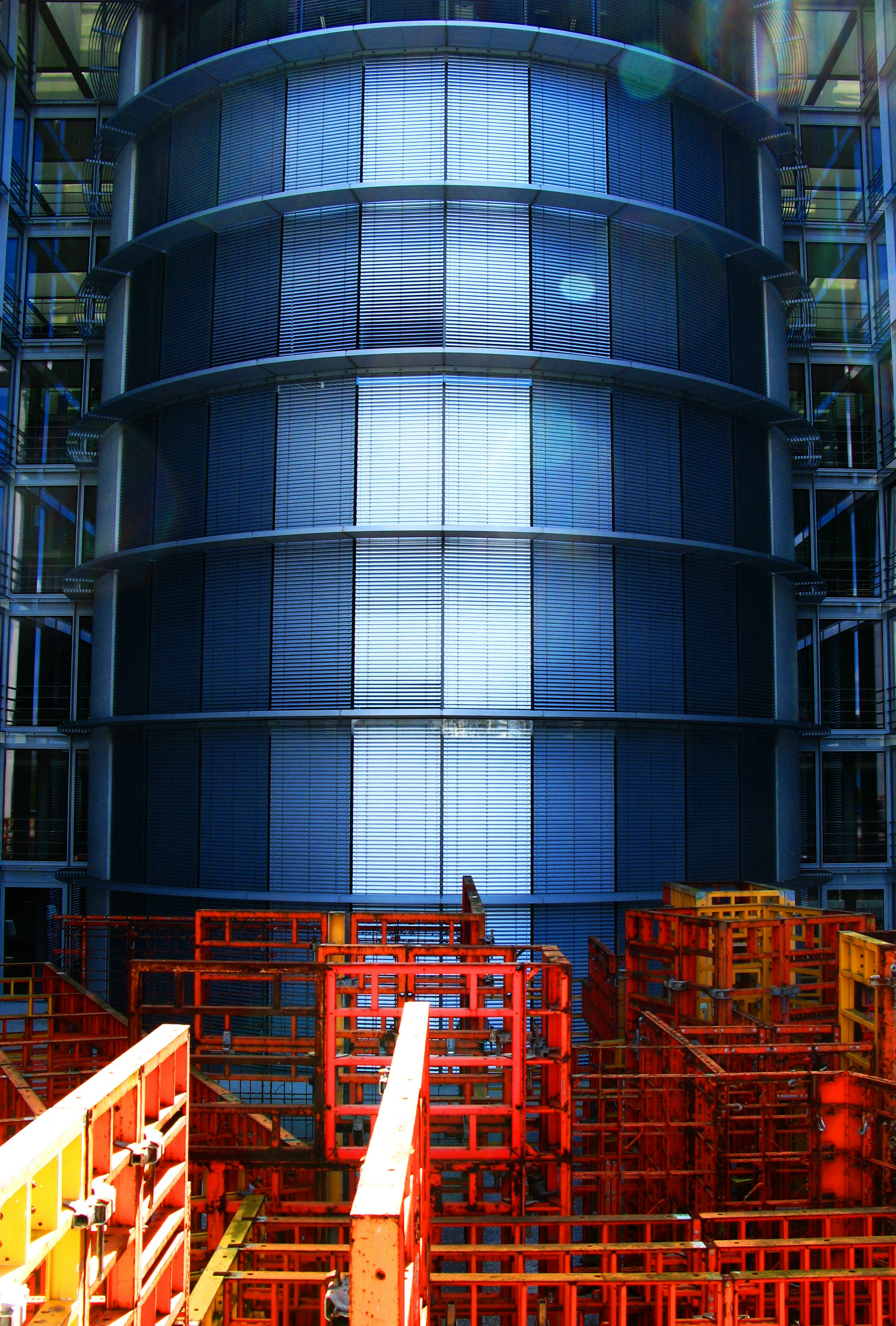 A striking view of a large cylindrical structure surrounded by vibrant orange scaffolding, showcasing the contrast between industrial design and color dynamics.